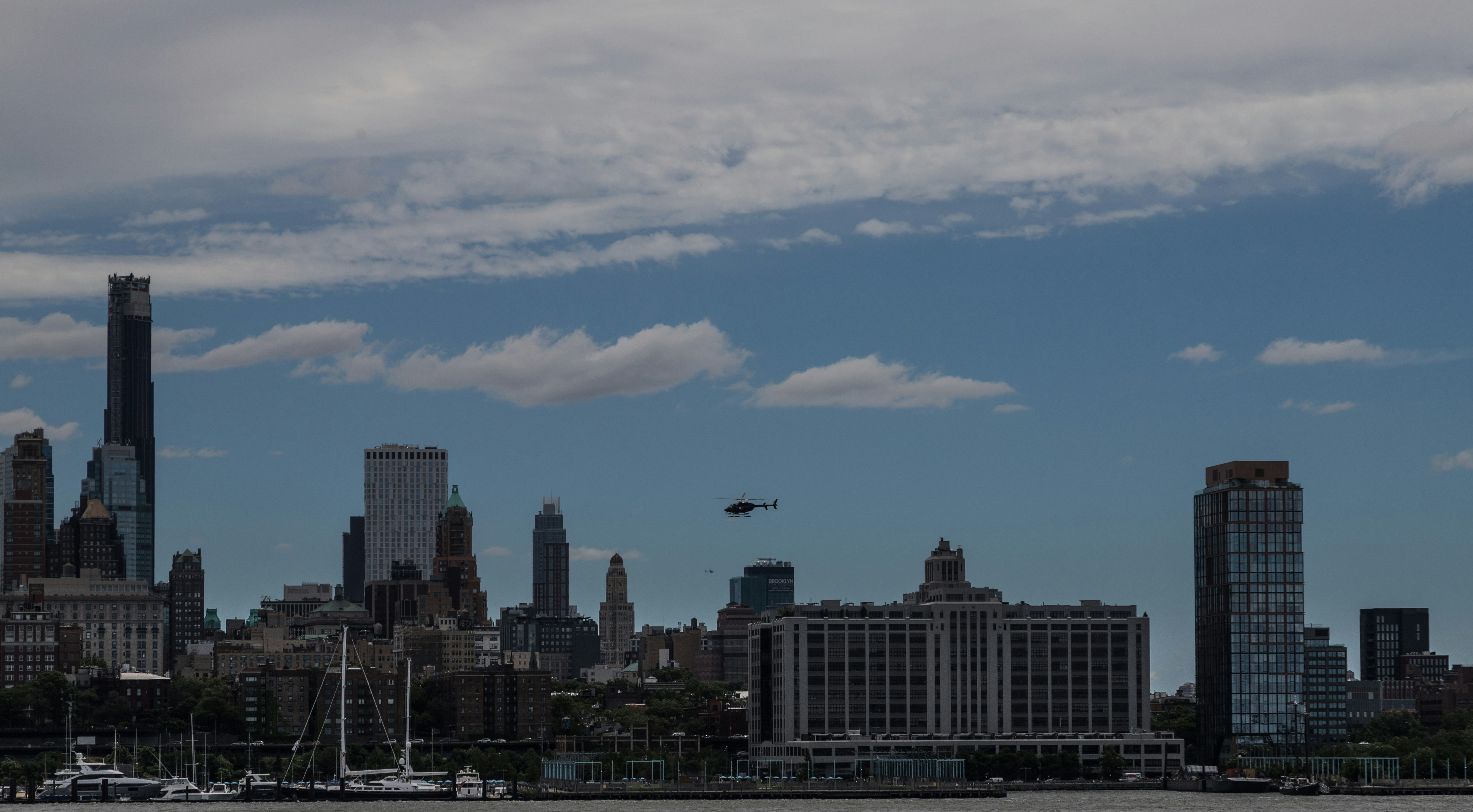 Helicopter Over the Harbor: A Swift Shadow Across a Glass Downtown Skyline
