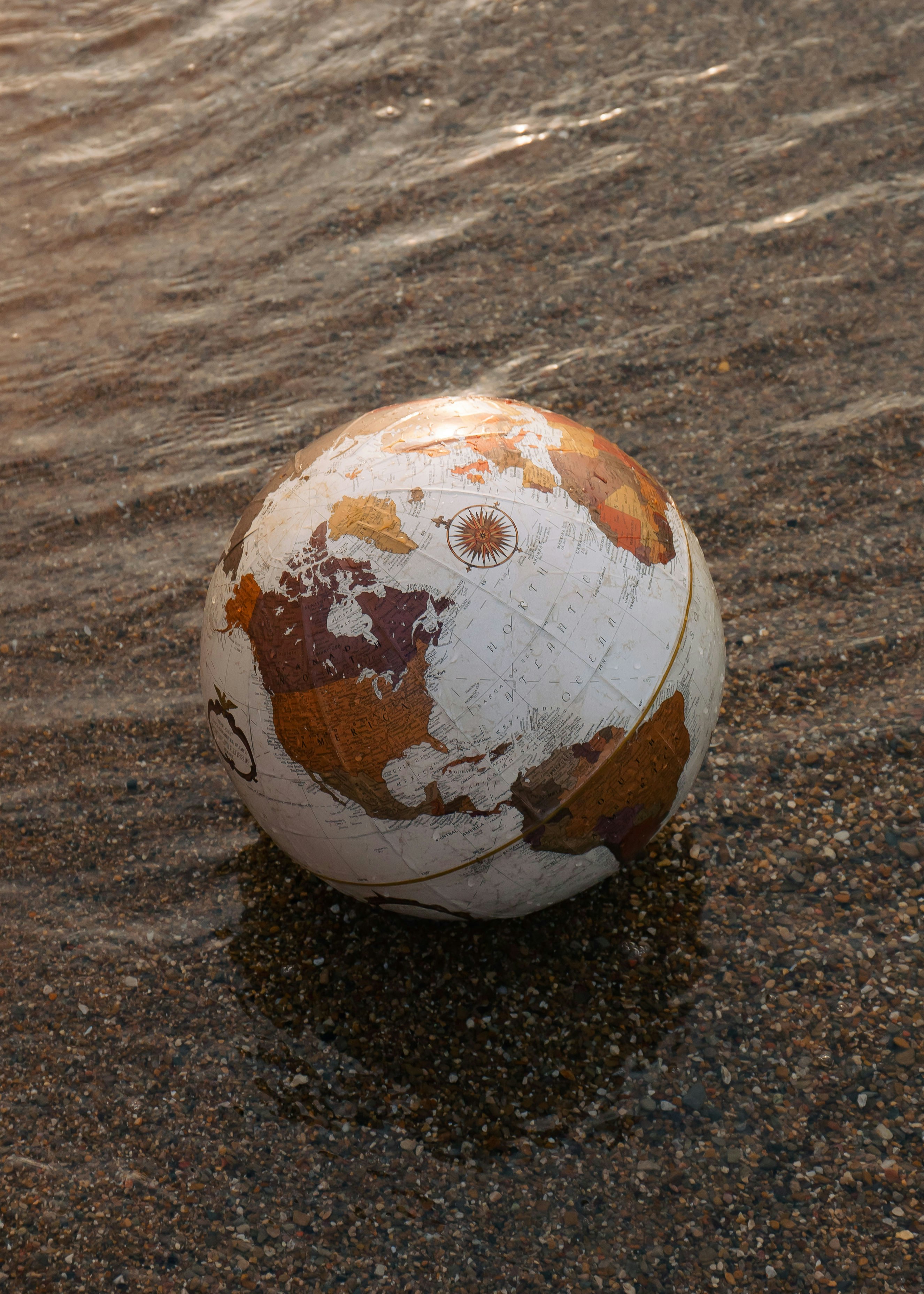 A worn out soccer ball sitting in the sand photo – Free Globe Image on ...