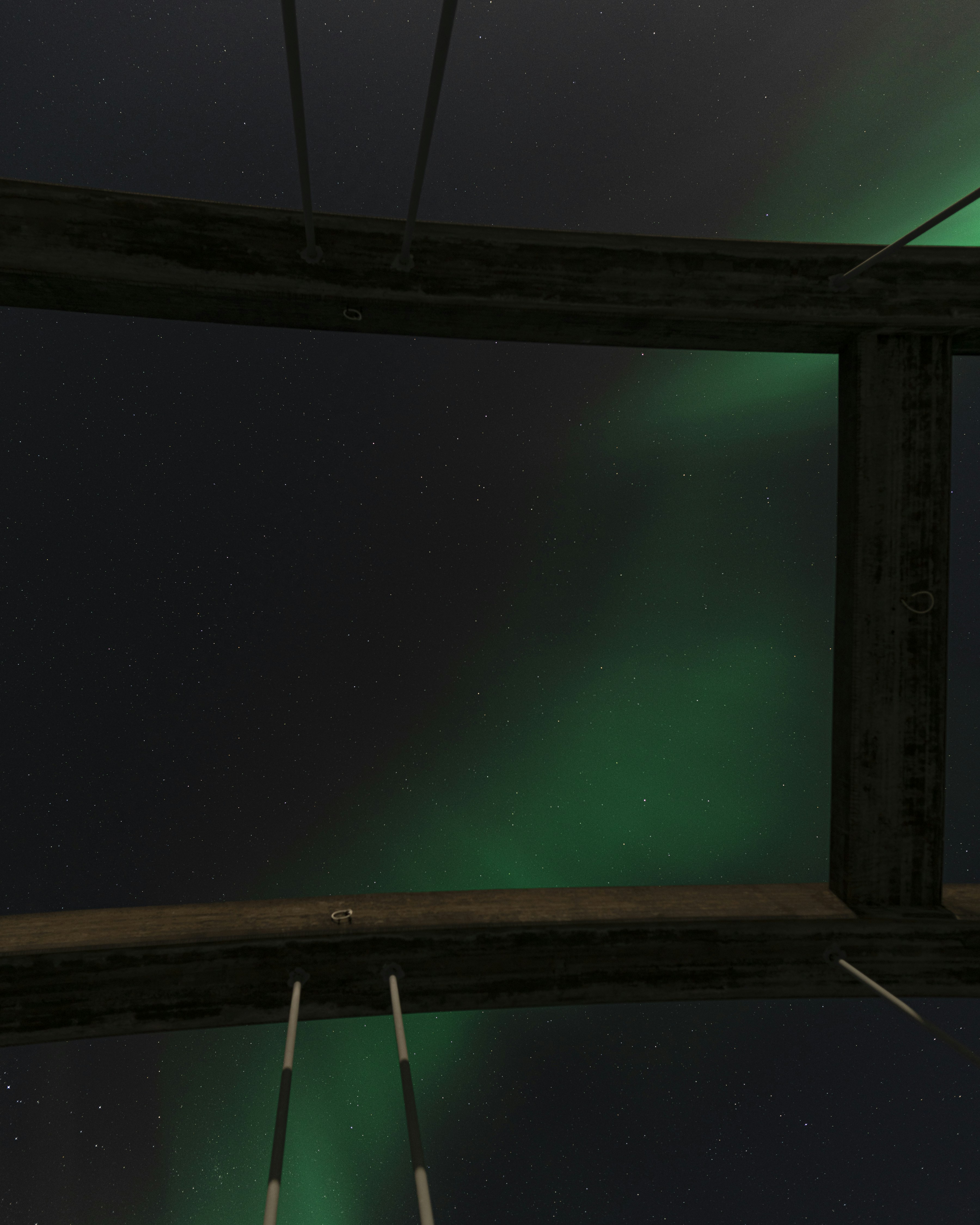 Aurora Through the Weathered Frame: Night Sky Over a Rustic Lookout