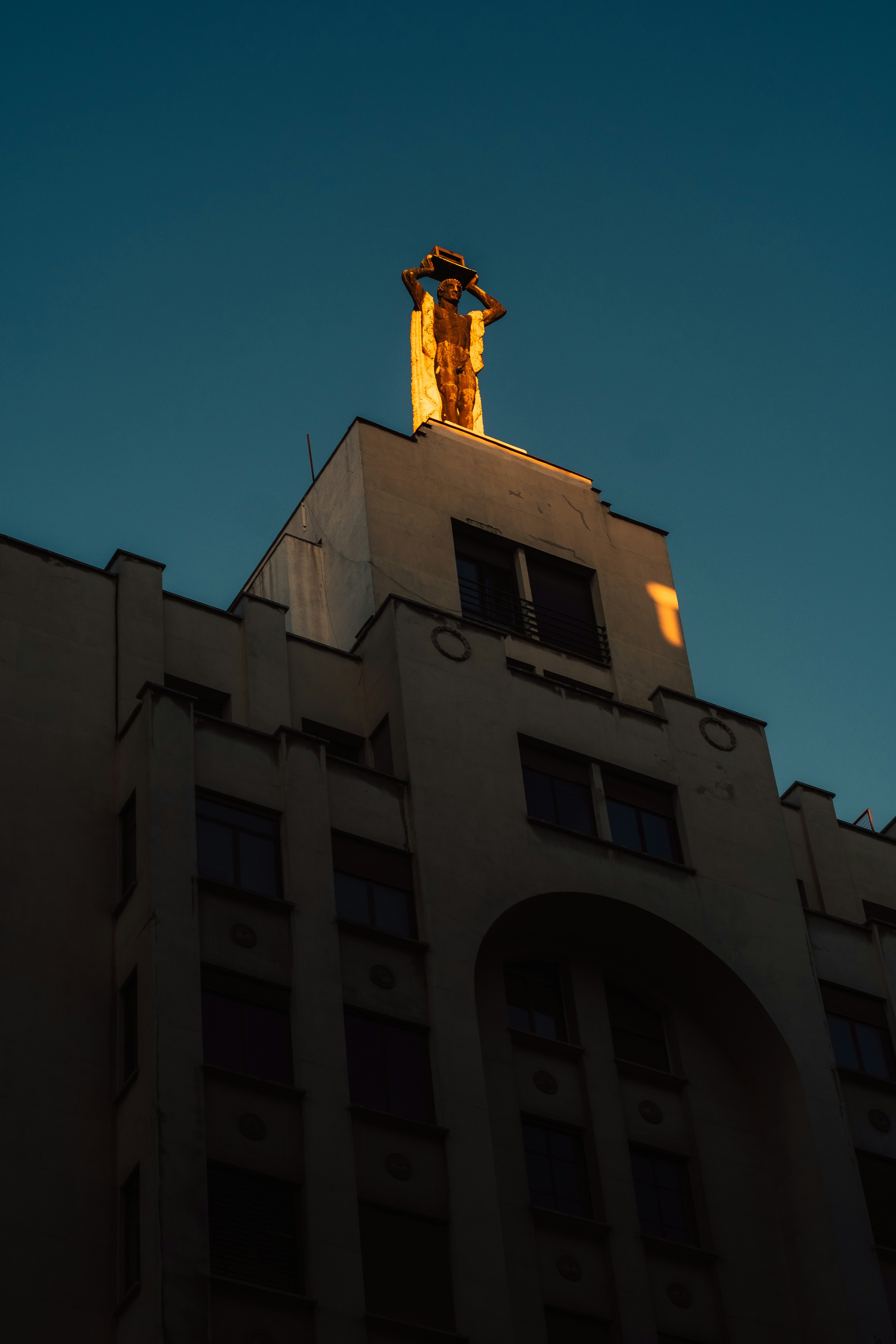 Sunlit Guardian on the Rooftop: A Statue Crowning the City