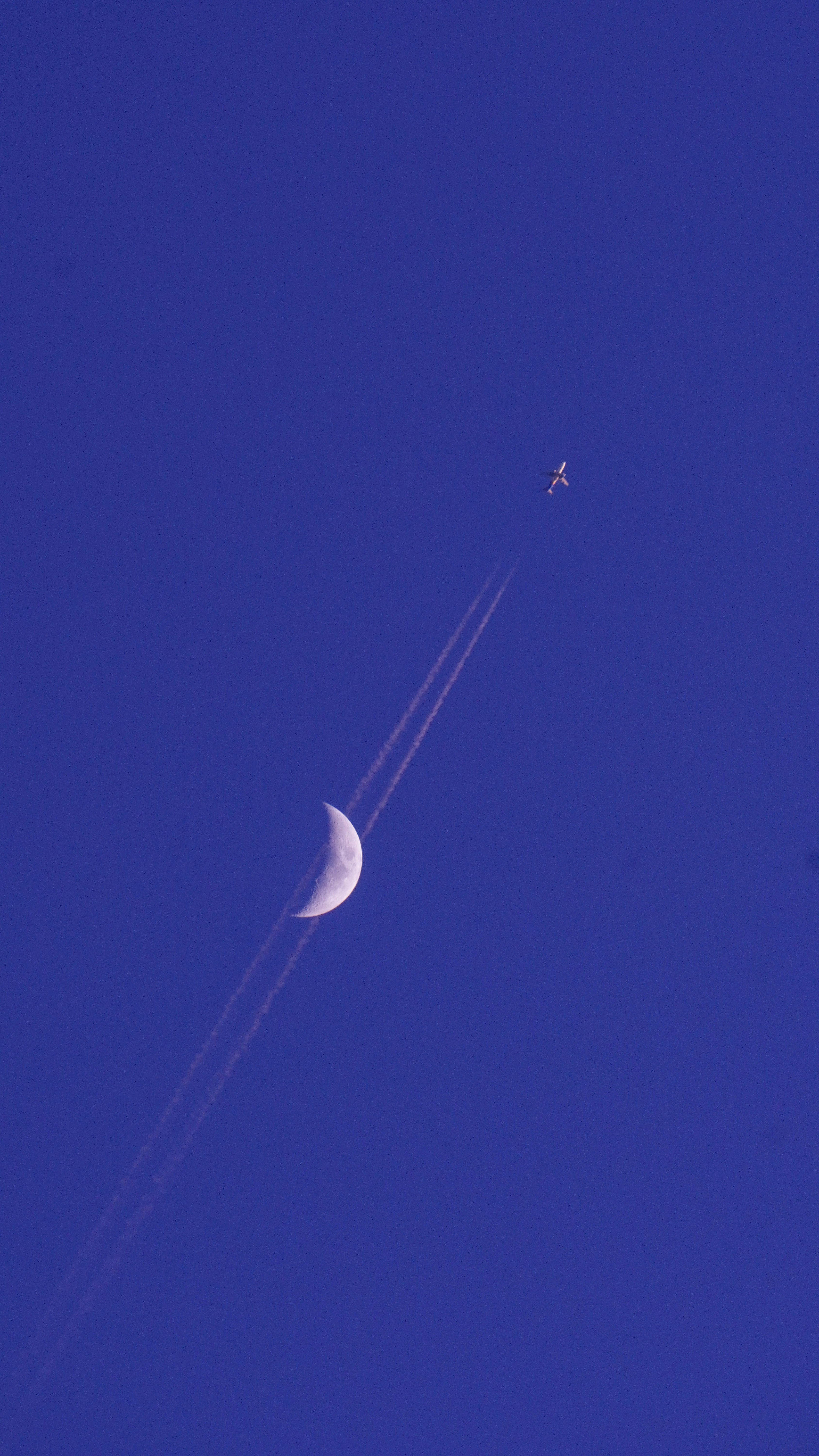 Blue Hour Trail: Contrails Crossing a Crescent Moon