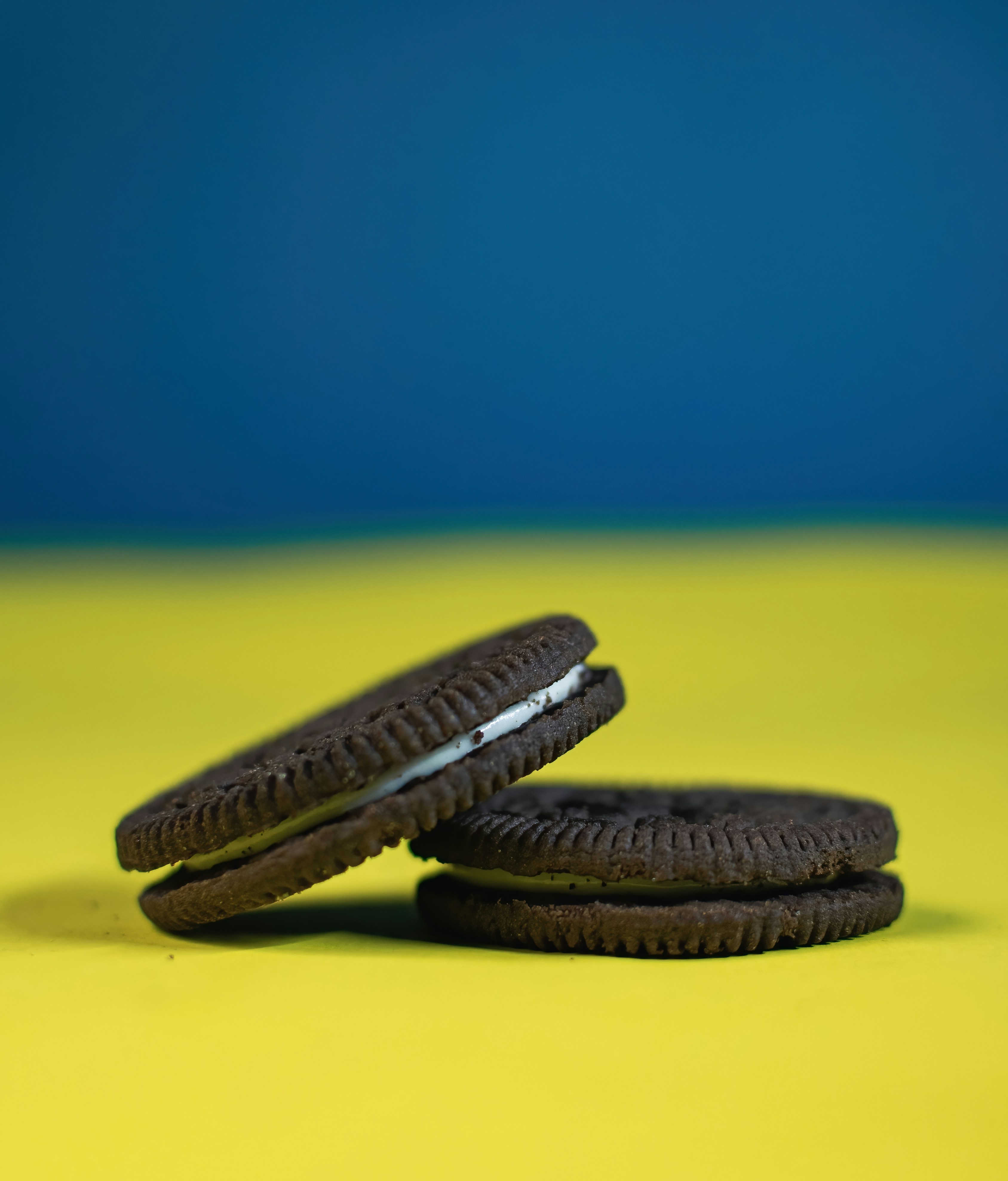 Two oreo cookies sitting on top of a yellow table photo – Free Food ...