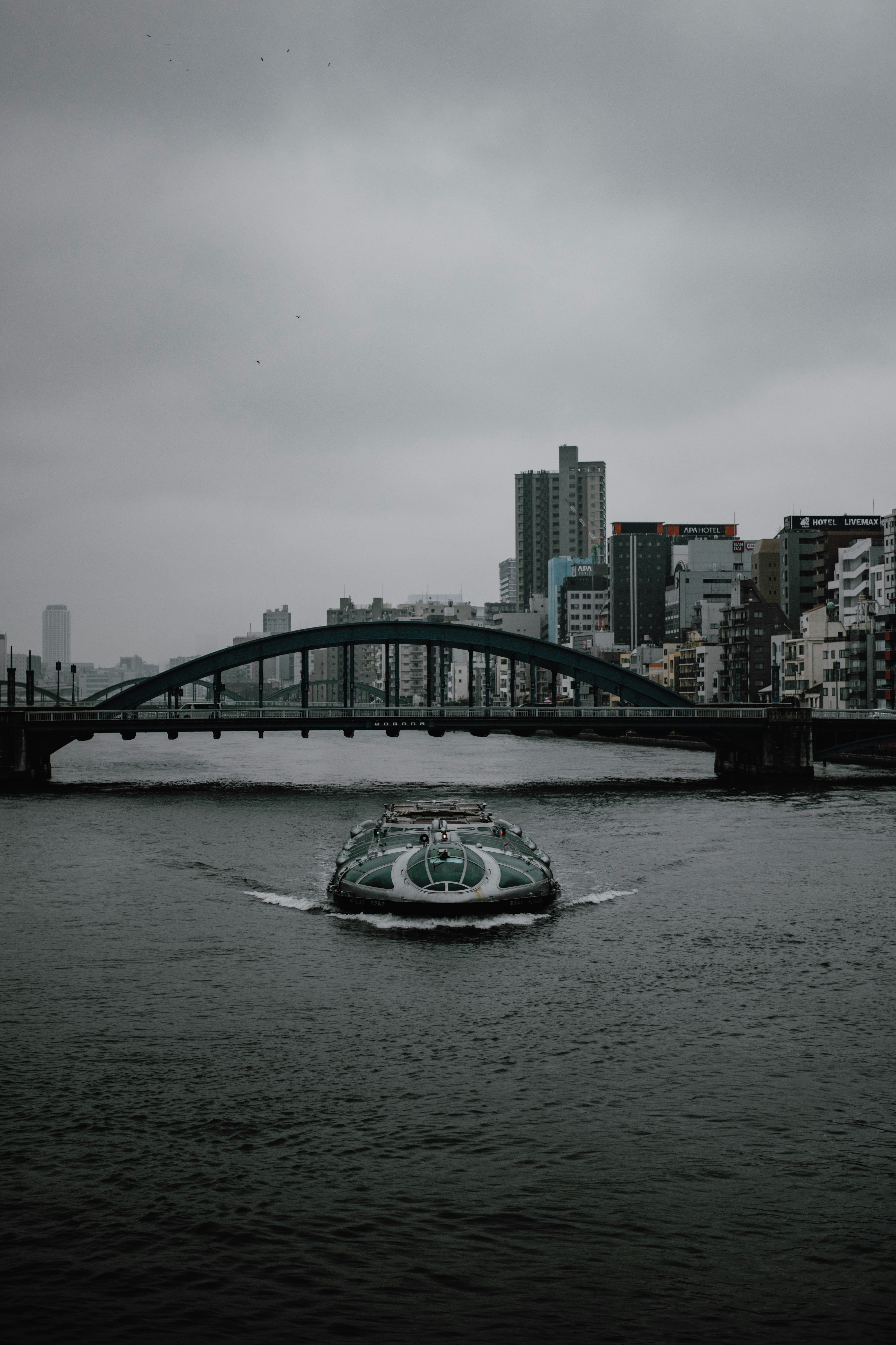 City Wake: A Green-Tinted Boat Under the Arch