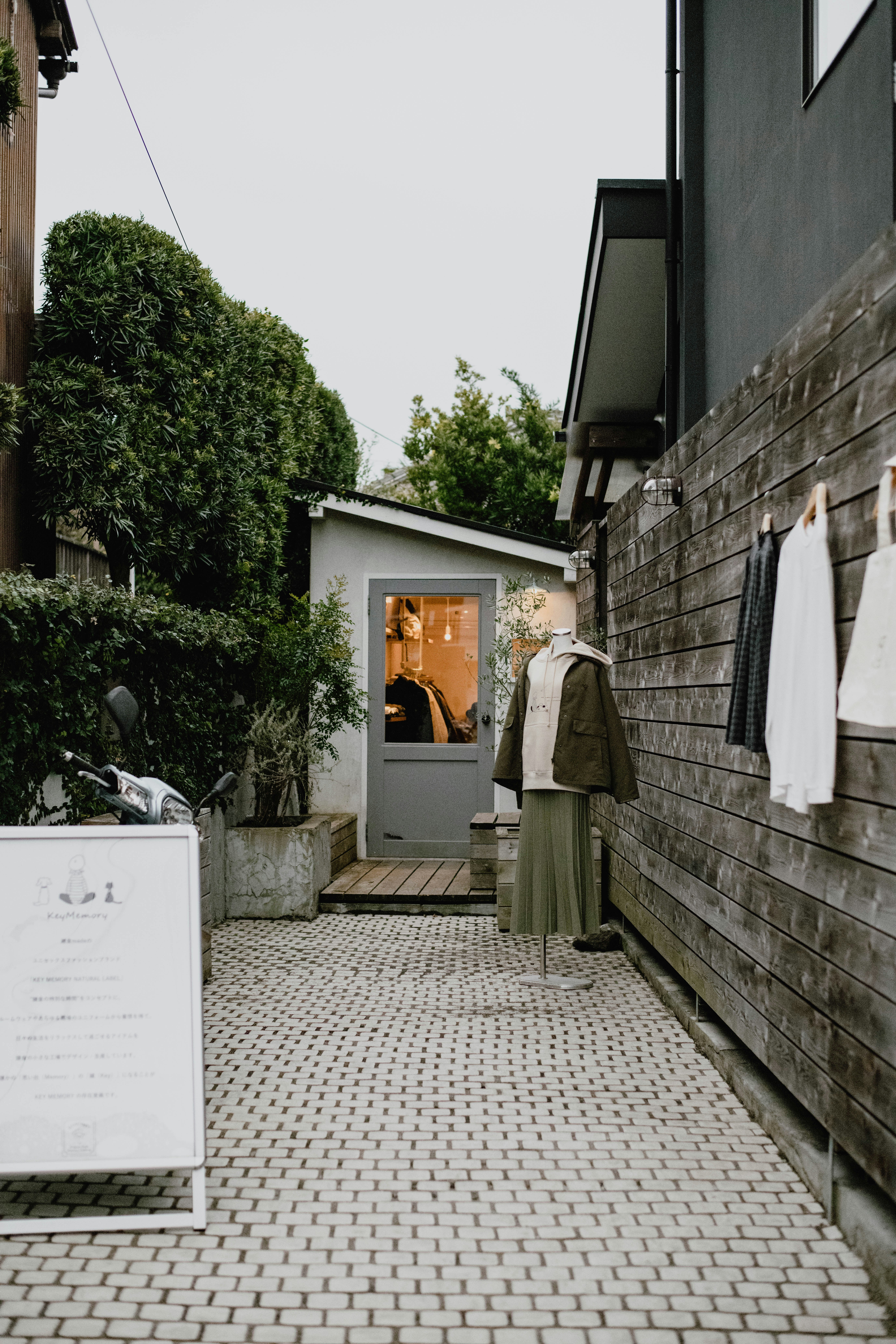 Masked Olive Coat in a Courtyard Shopfront