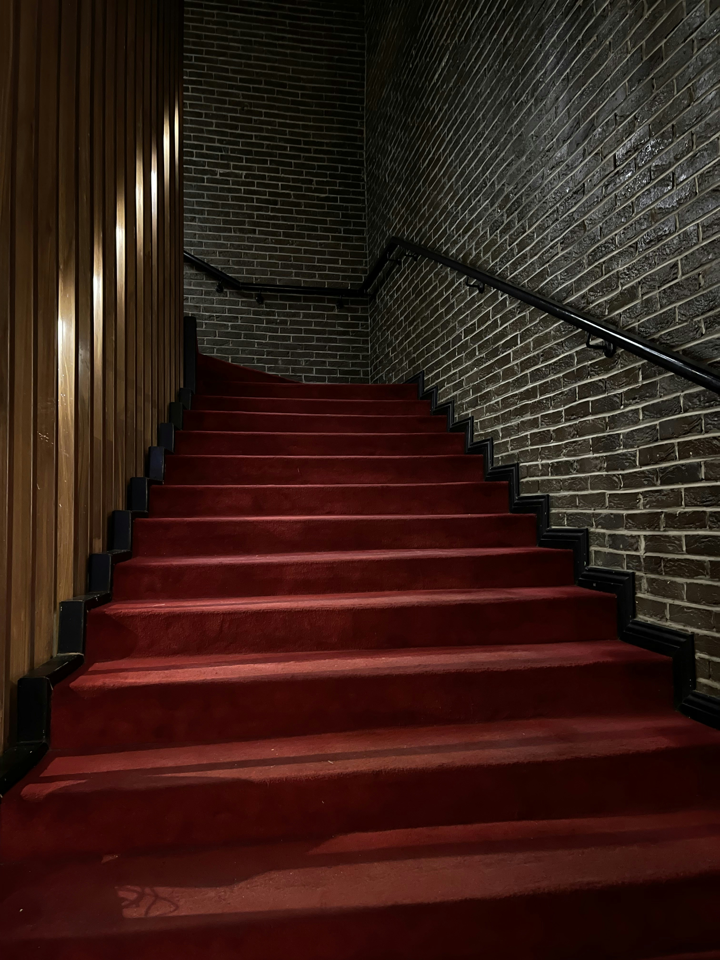 Crimson Carpet Staircase Framed by Brick Walls and Wooden Slats