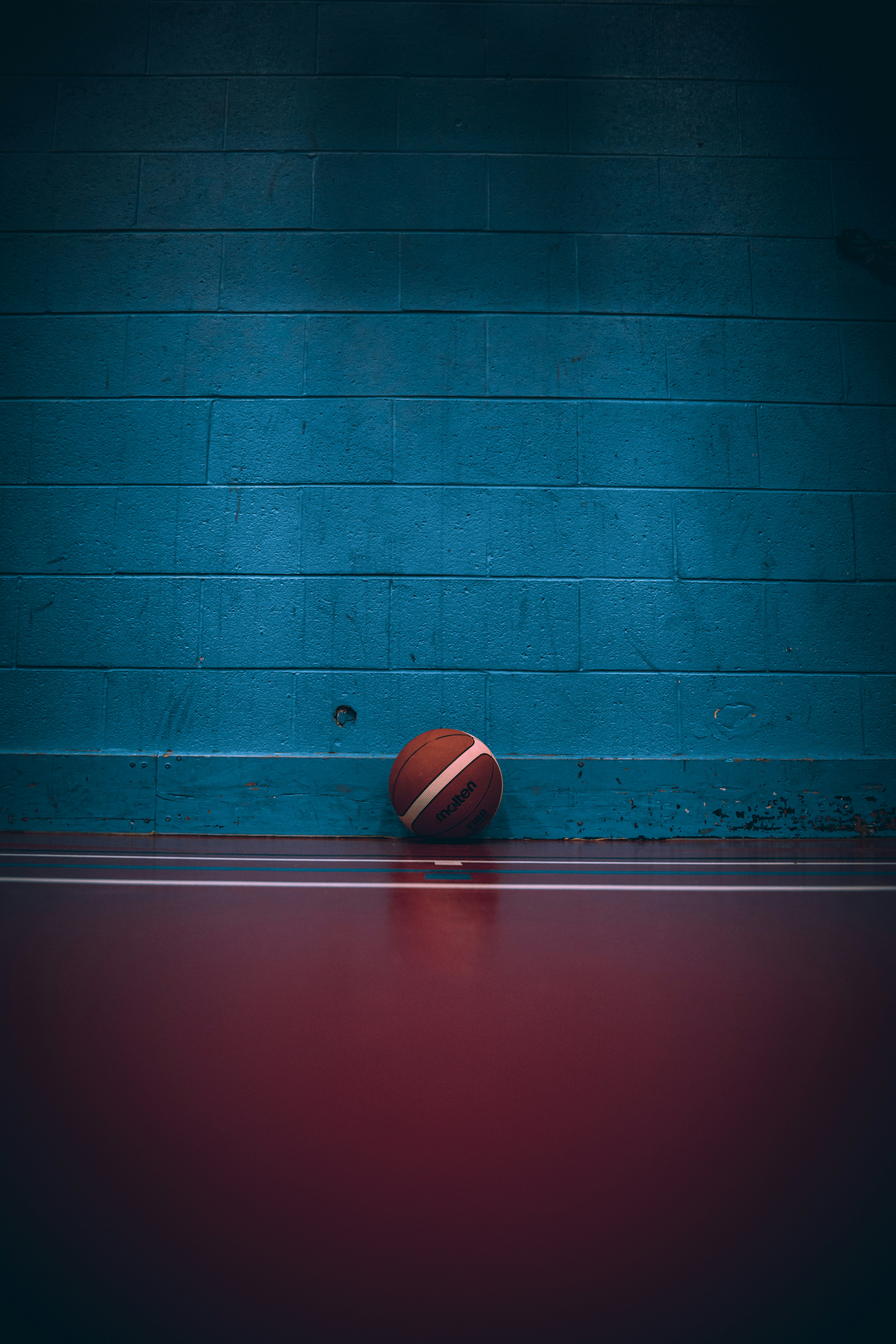 Ballad of the Court: A lone basketball at the edge of a blue wall