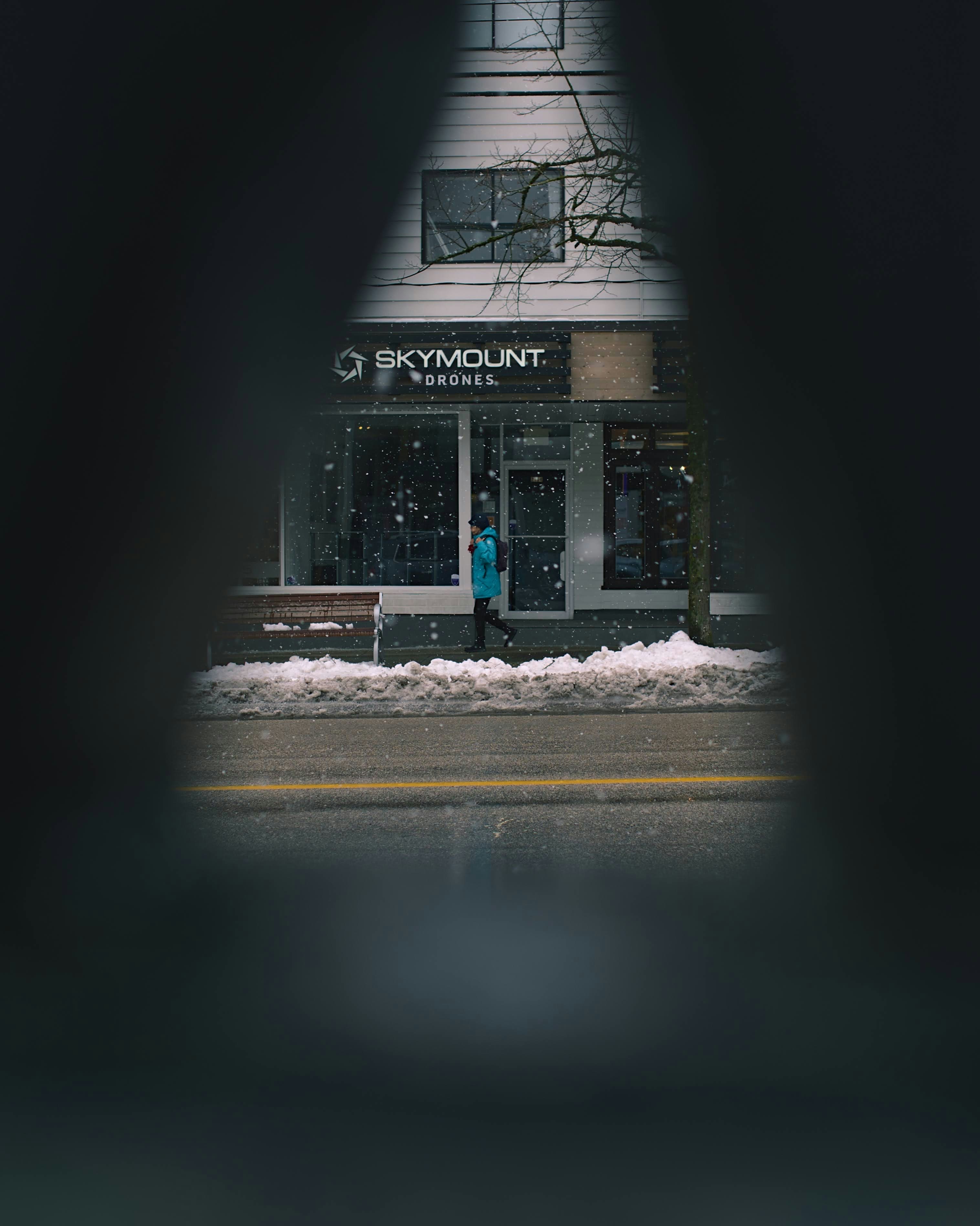 Blue Coat on a Snowy Street: Framing the Skymount Drones storefront