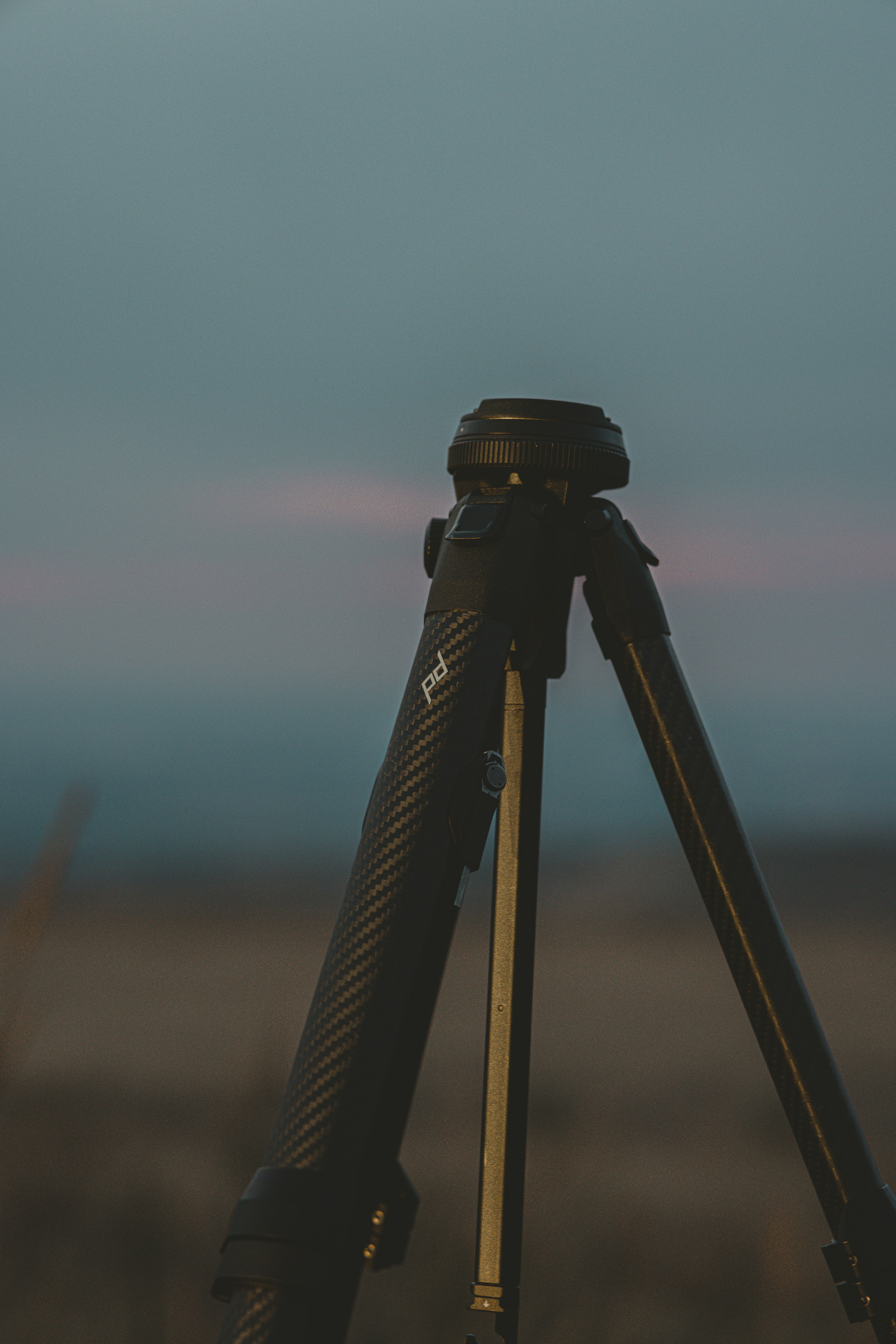 Tripod in silhouette: a lone camera support against a dusky horizon