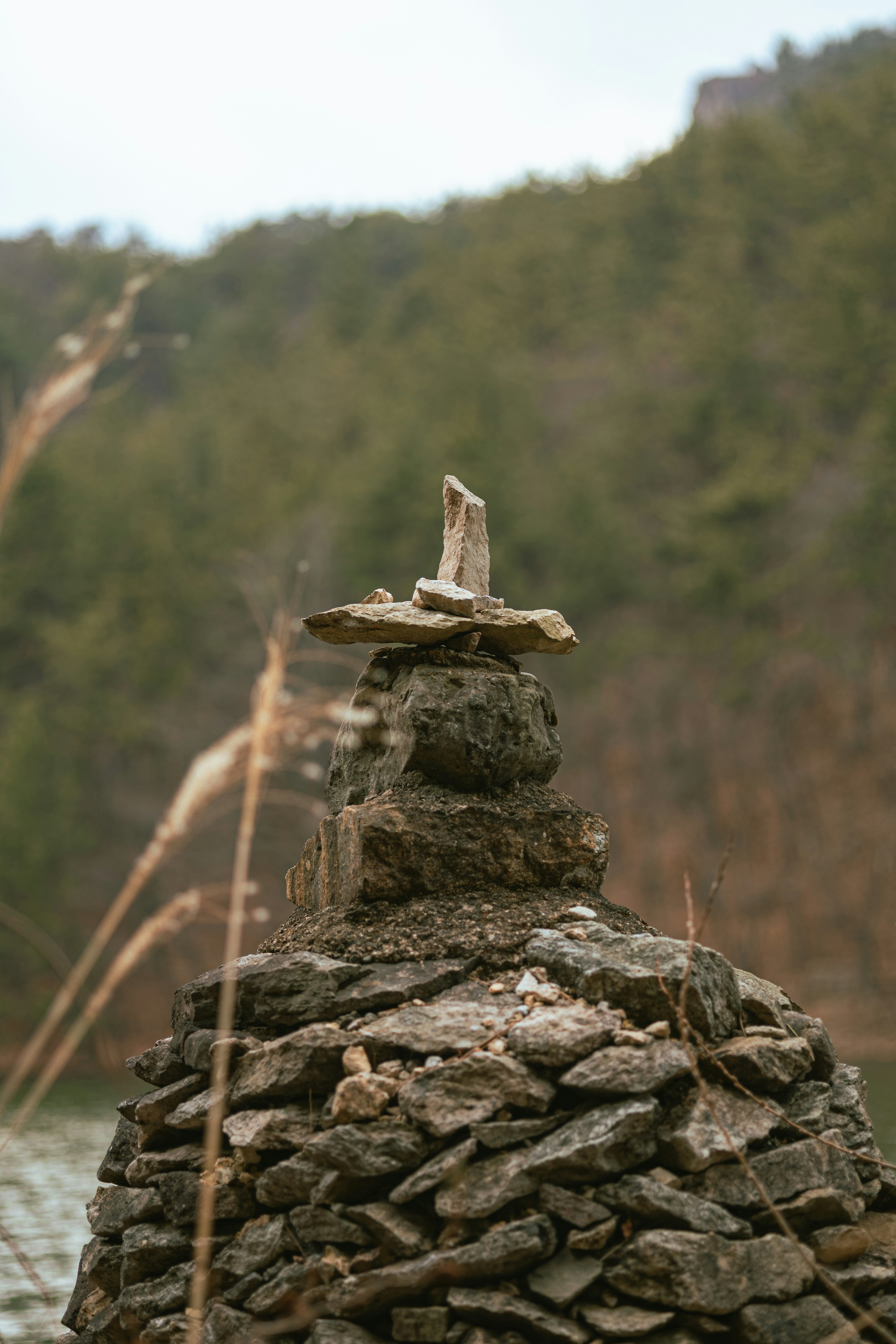 Balanced Cairn Framing a Forested Lakeshore