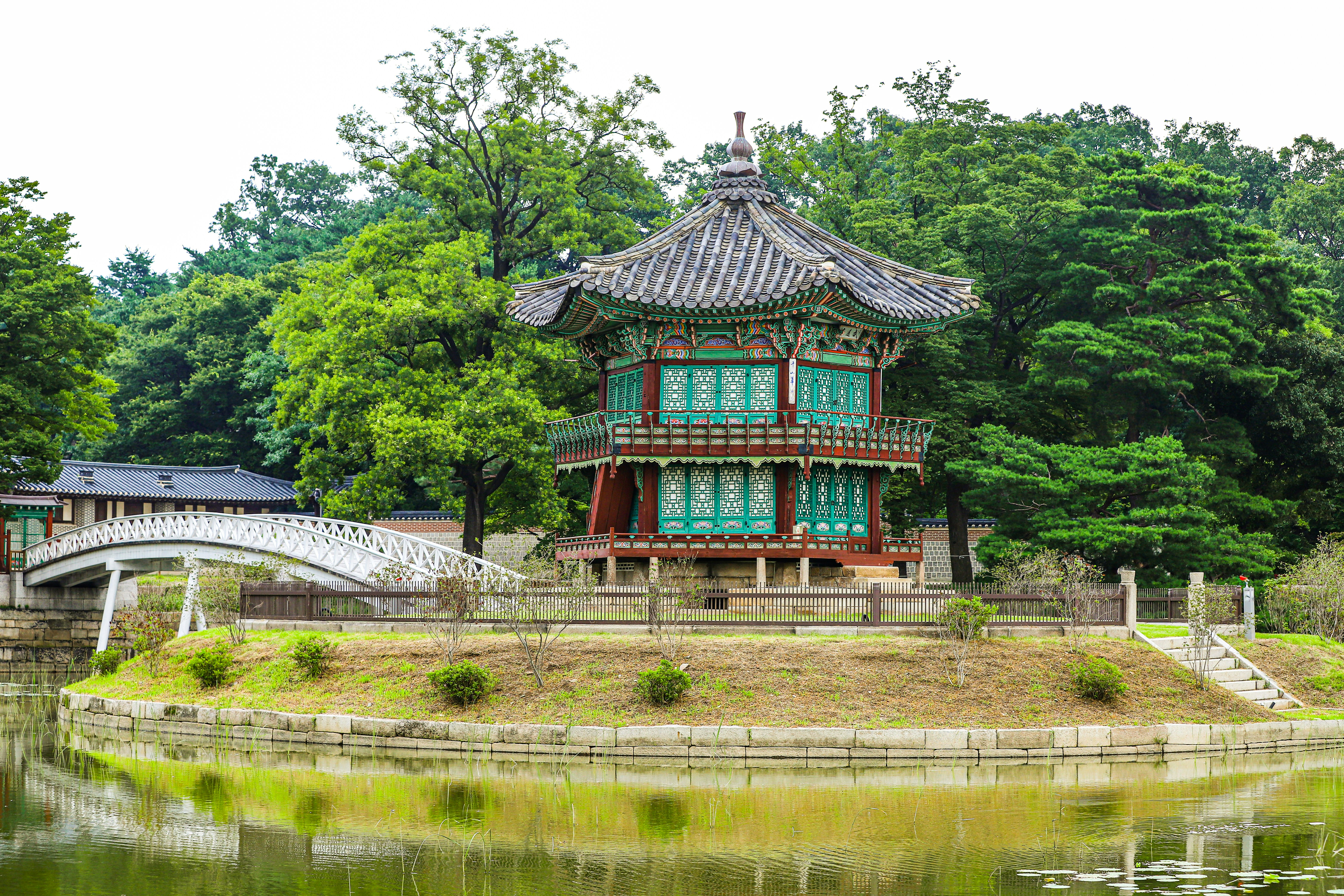 Traditional pavilion surrounded by lush greenery and reflected in a tranquil pond.
