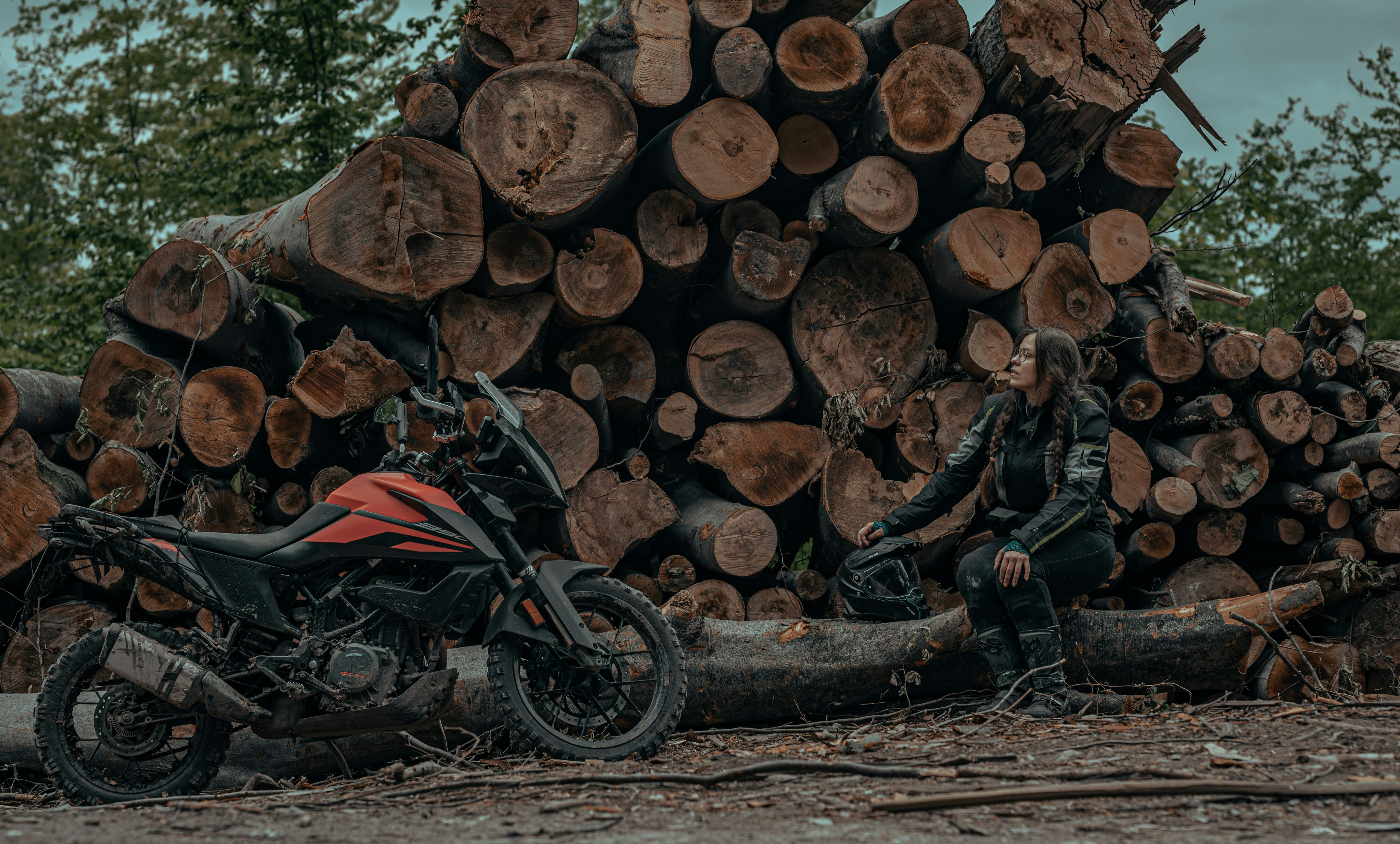 Logs, Steel, and Solitude: Rider Resting by the Timber Stack