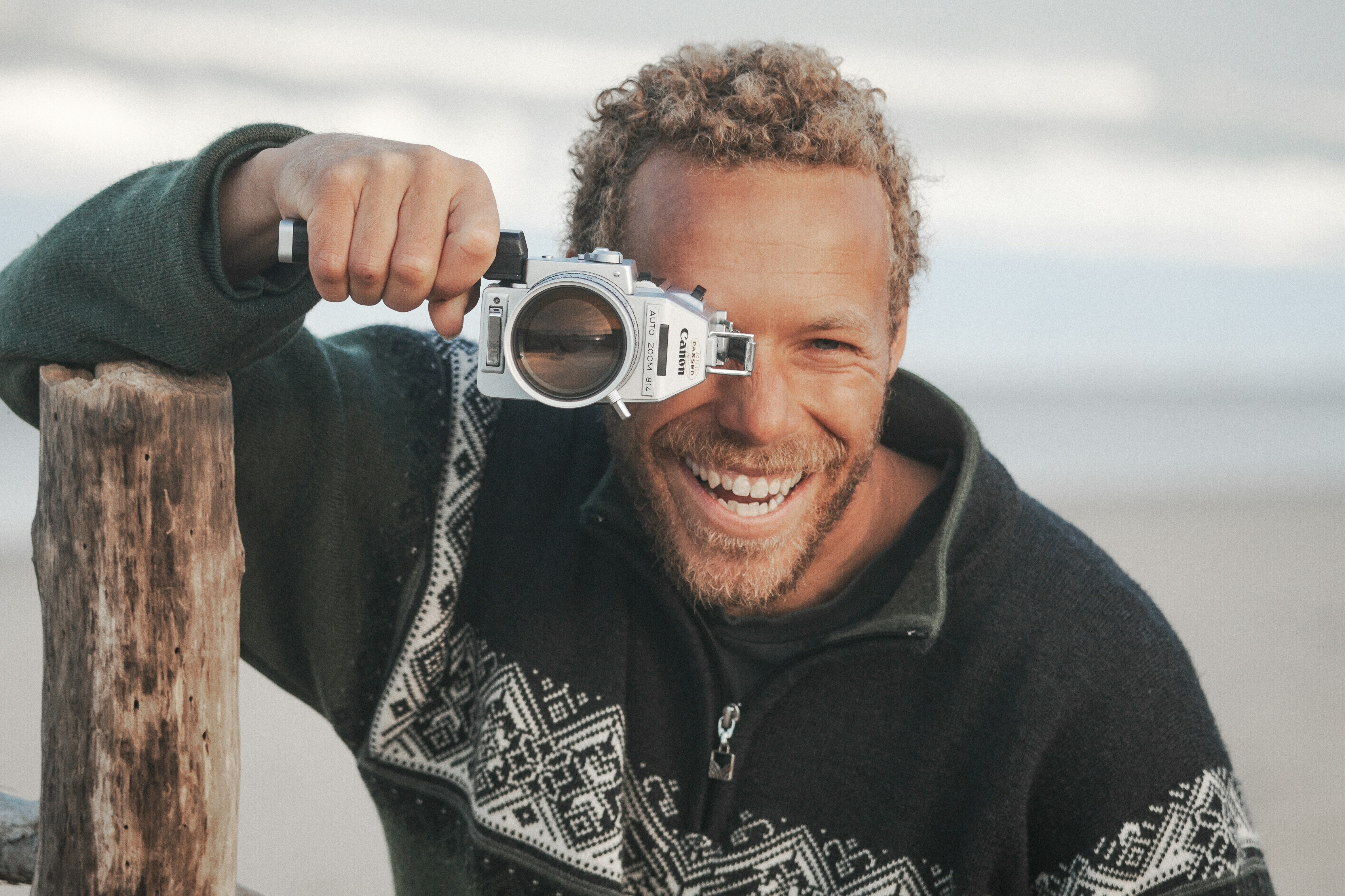 Shoreline Smile: A Beach Portrait Framed by a Compact Silver Camera