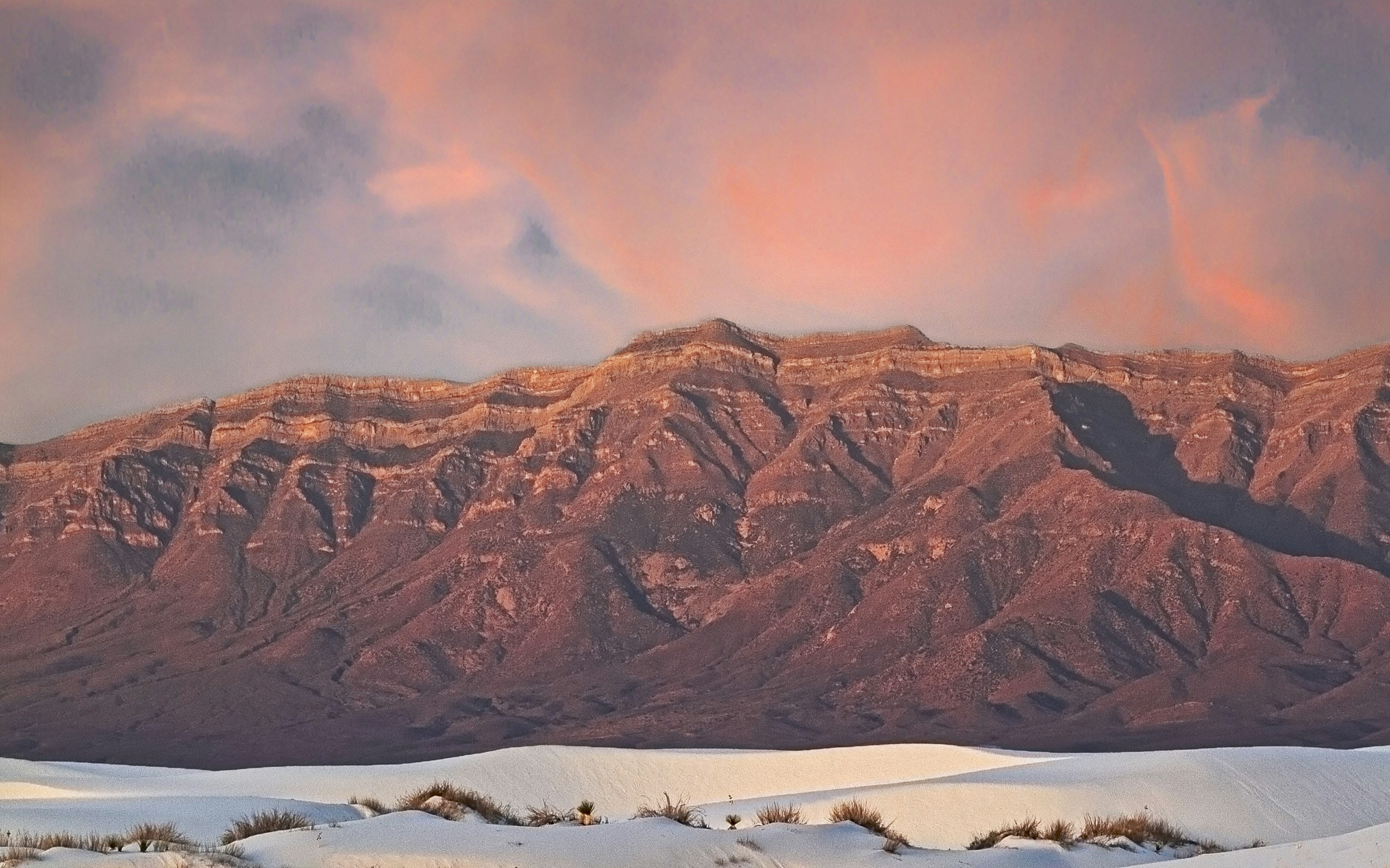a mountain range covered in snow under a cloudy sky