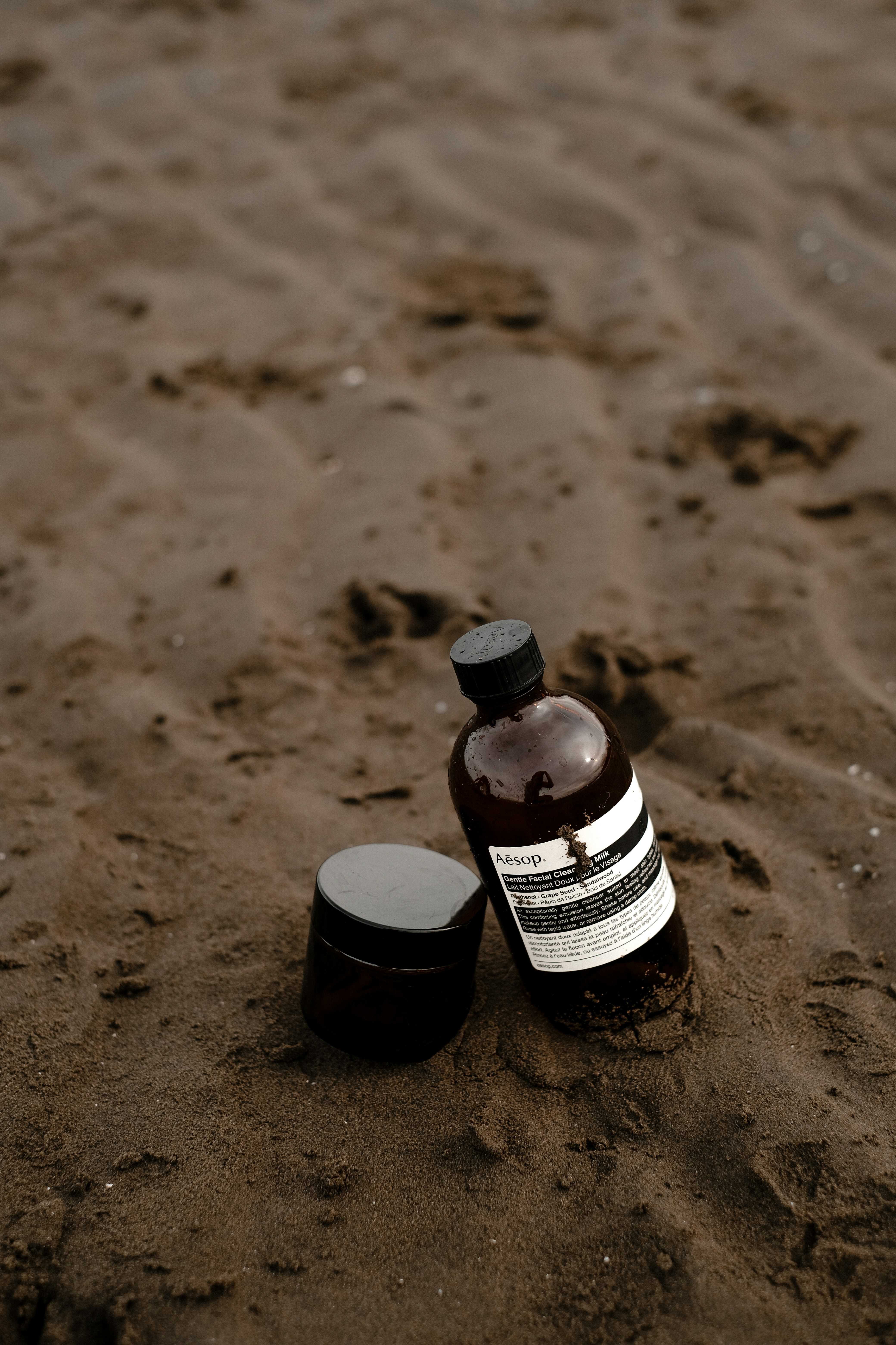 a bottle of lotion sitting in the sand