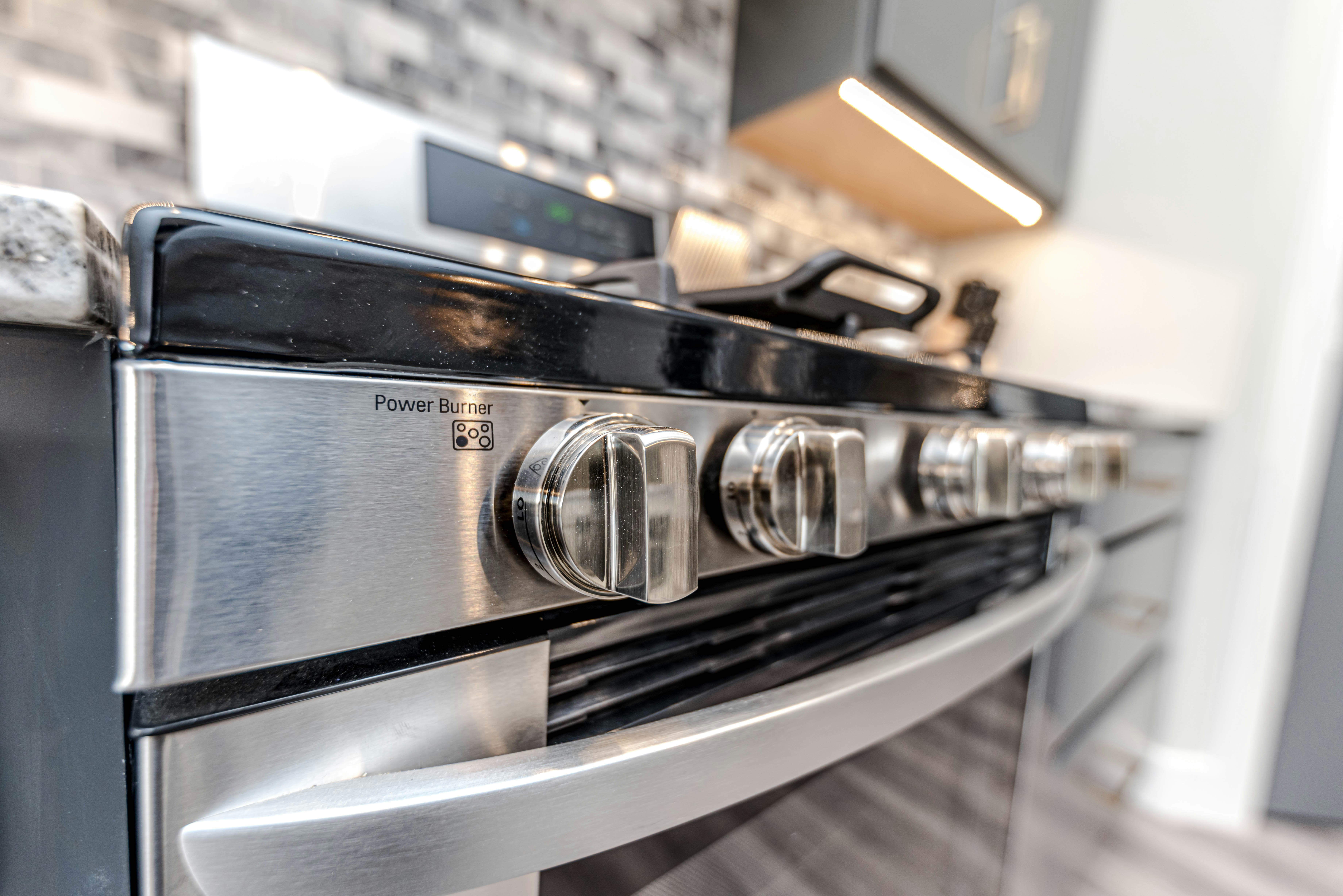 Close-up of a modern stainless steel gas stove with clear knobs and a sleek design, showcasing its power burner feature.
