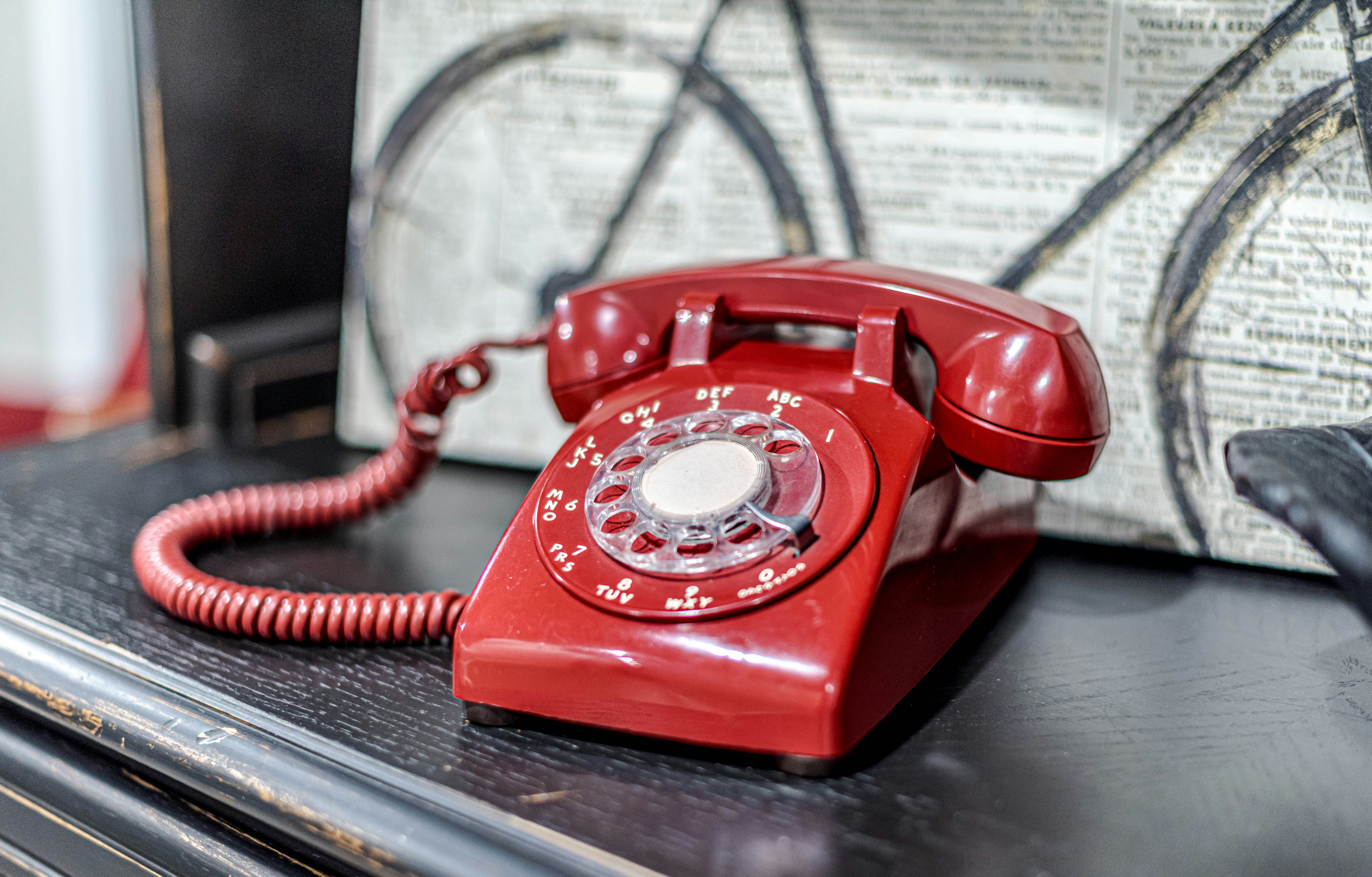 A red telephone sitting on top of a table photo – Free Phone Image on ...