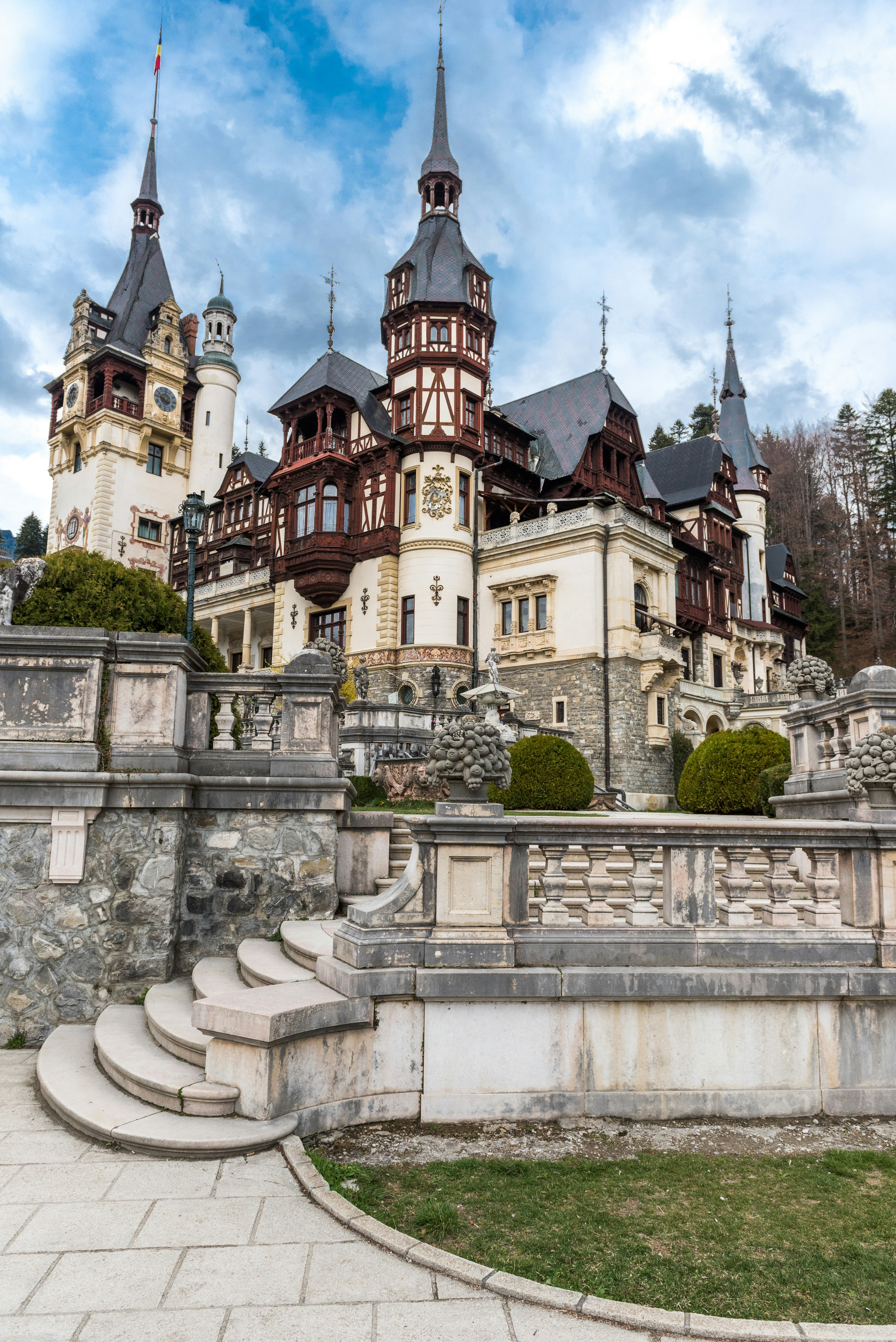 Elaborate castle featuring a blend of Gothic and Renaissance styles, surrounded by manicured gardens and stone pathways.
