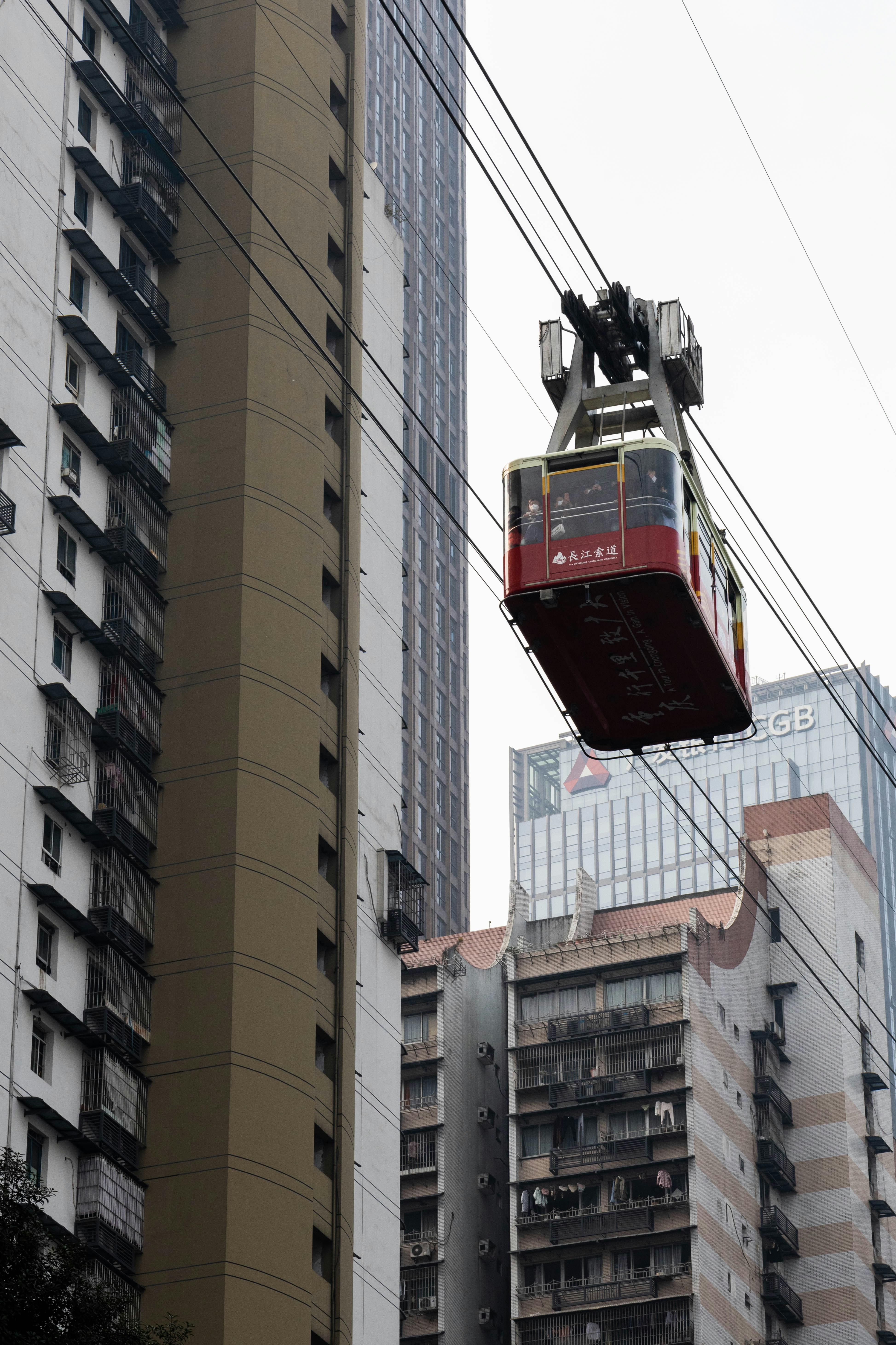 Red Cable Car Between Skyscrapers: A Narrow Transit Through the Concrete Canopy