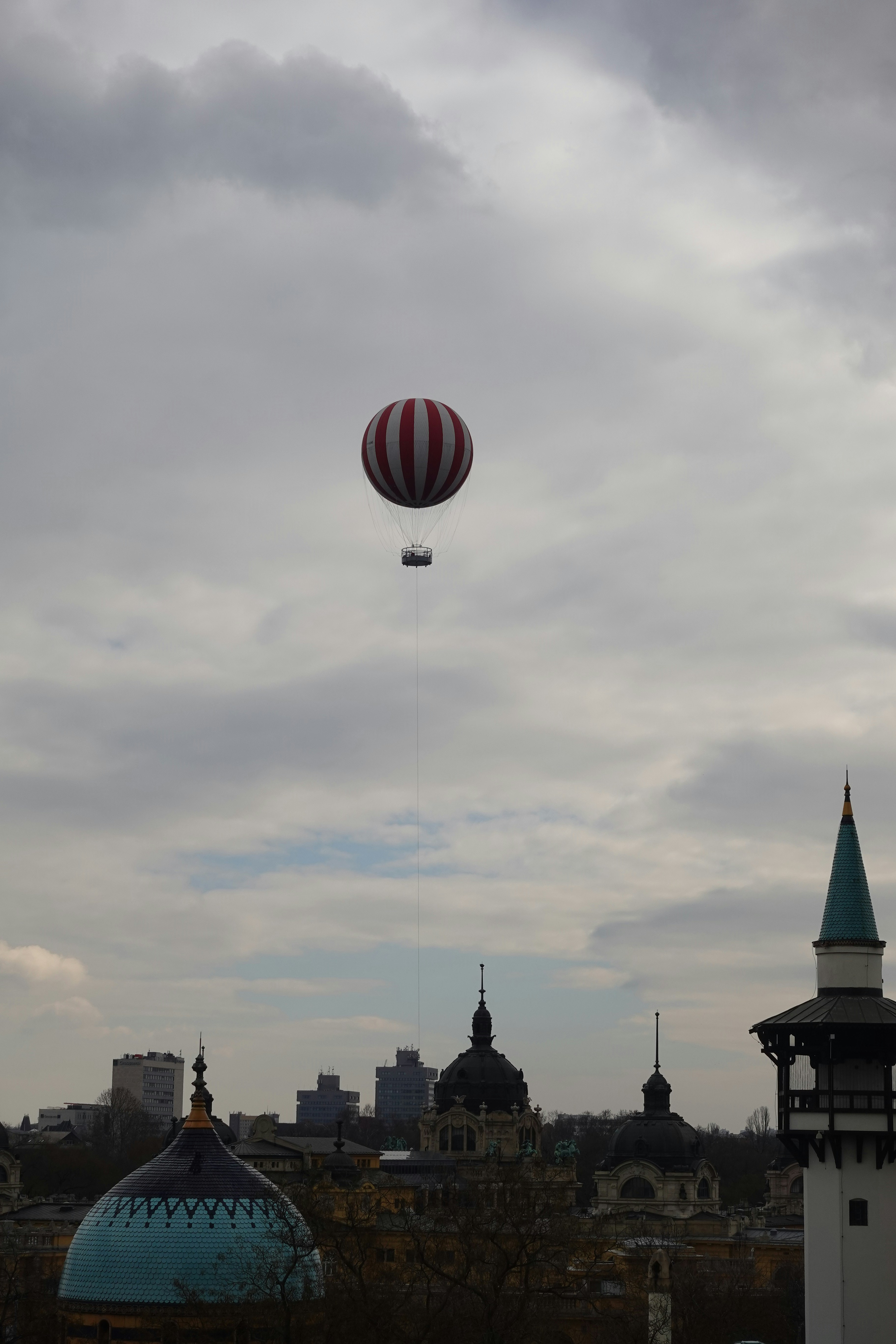 Crimson Balloon Drifts Over a Turreted Cityscape Beneath a Cloudy Sky
