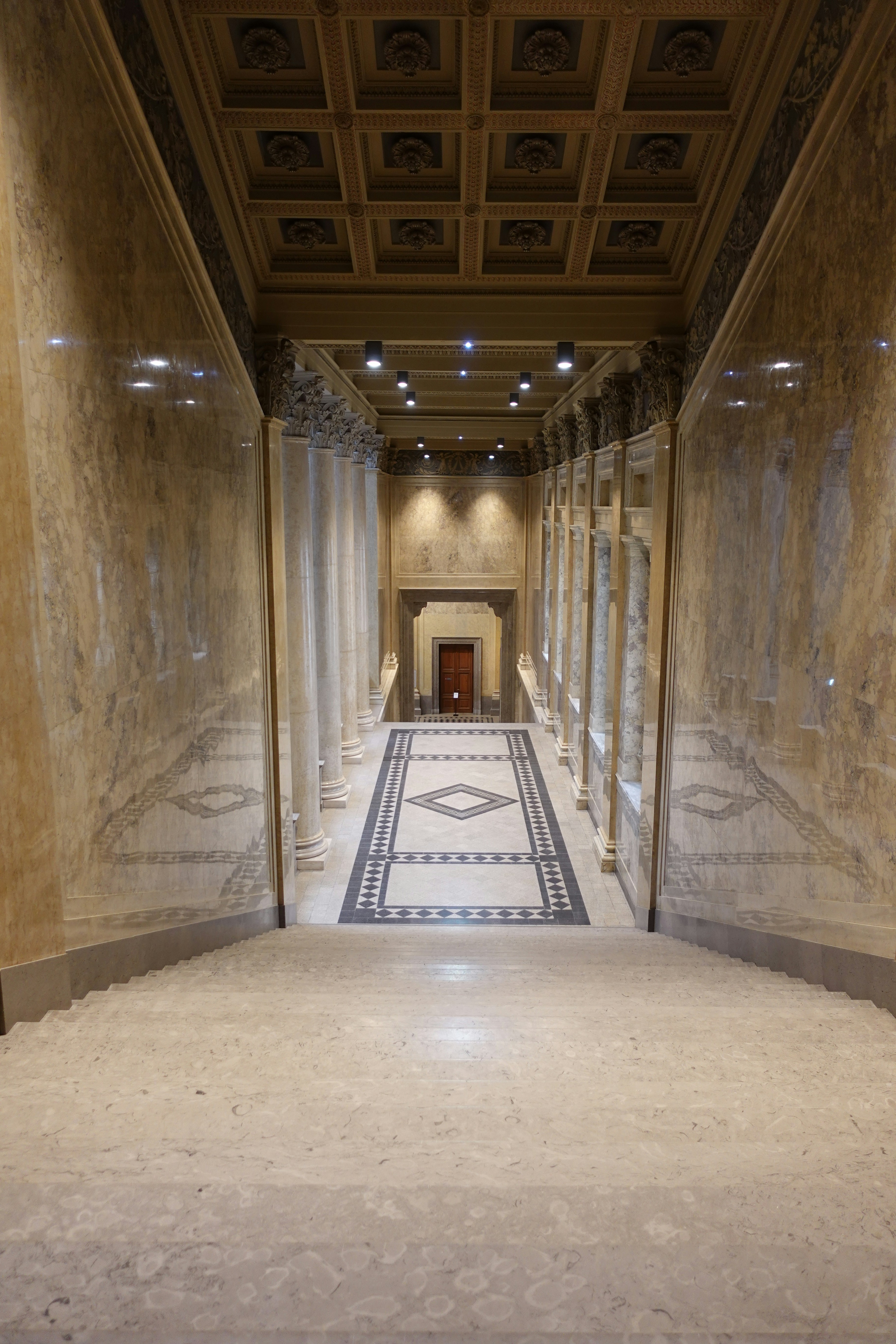 A long hallway with columns and a door photo – Free Floor Image on Unsplash