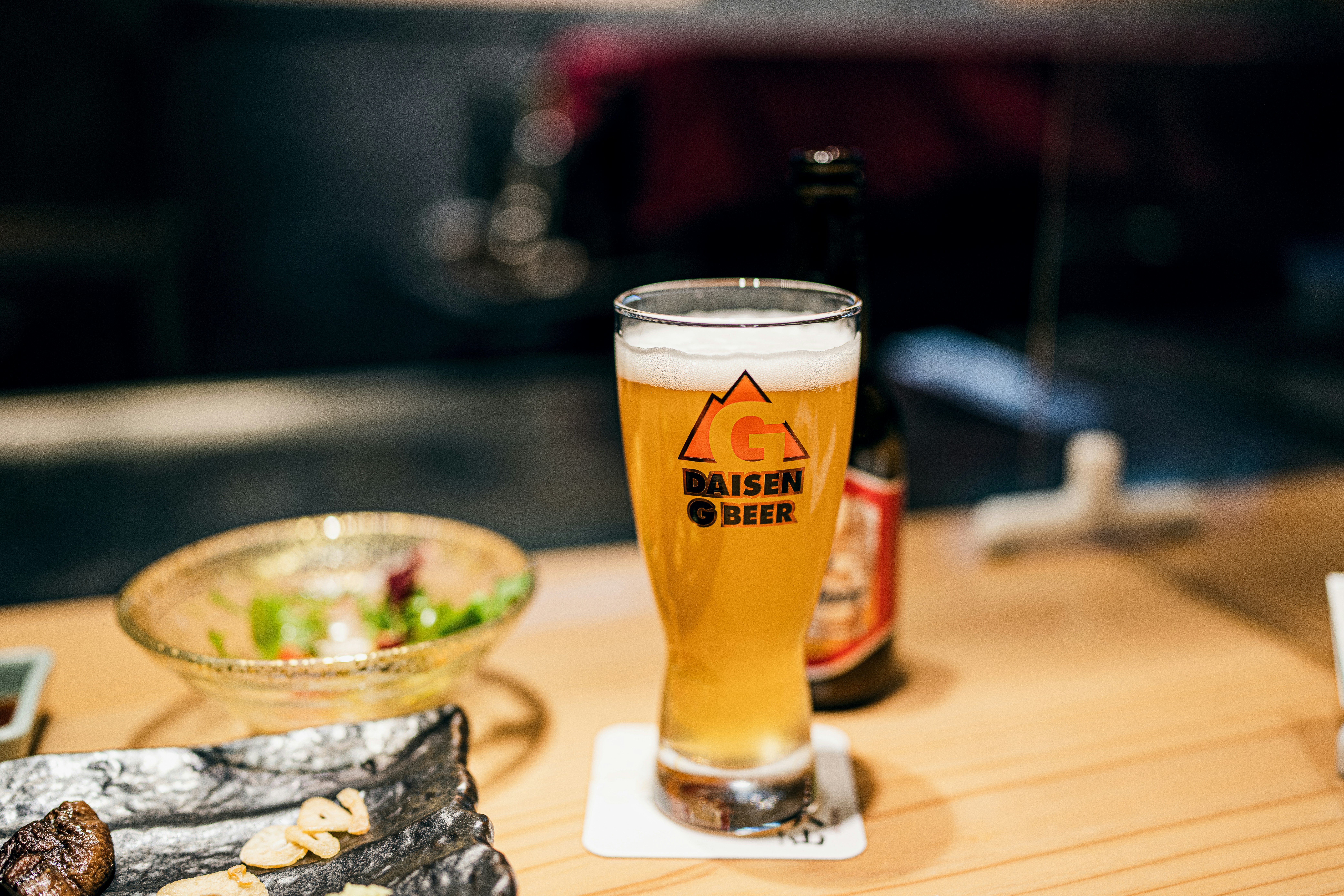 a glass of beer sitting on top of a wooden table