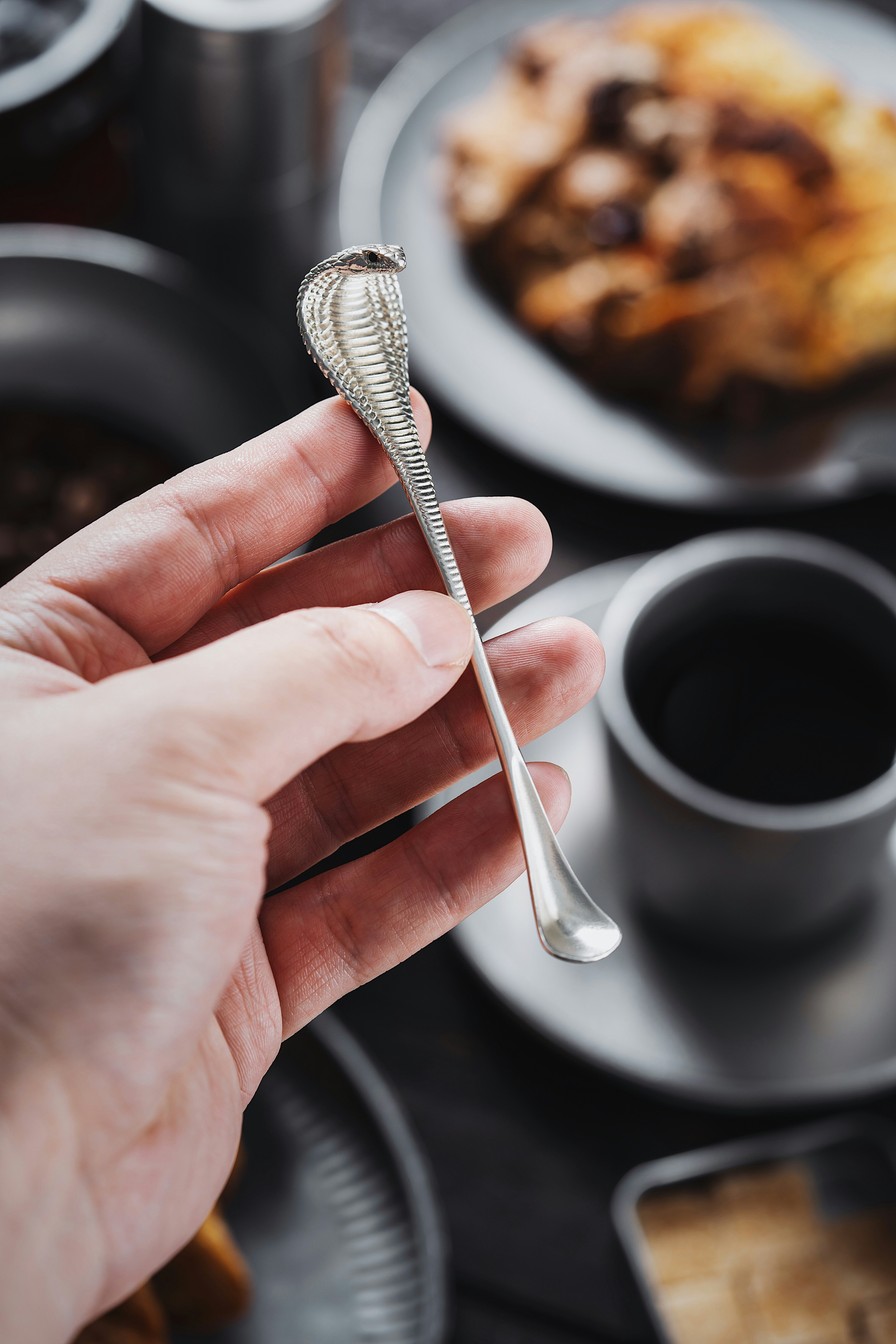 Tensioned snare: a delicate cobra spoon held above a kitchen table