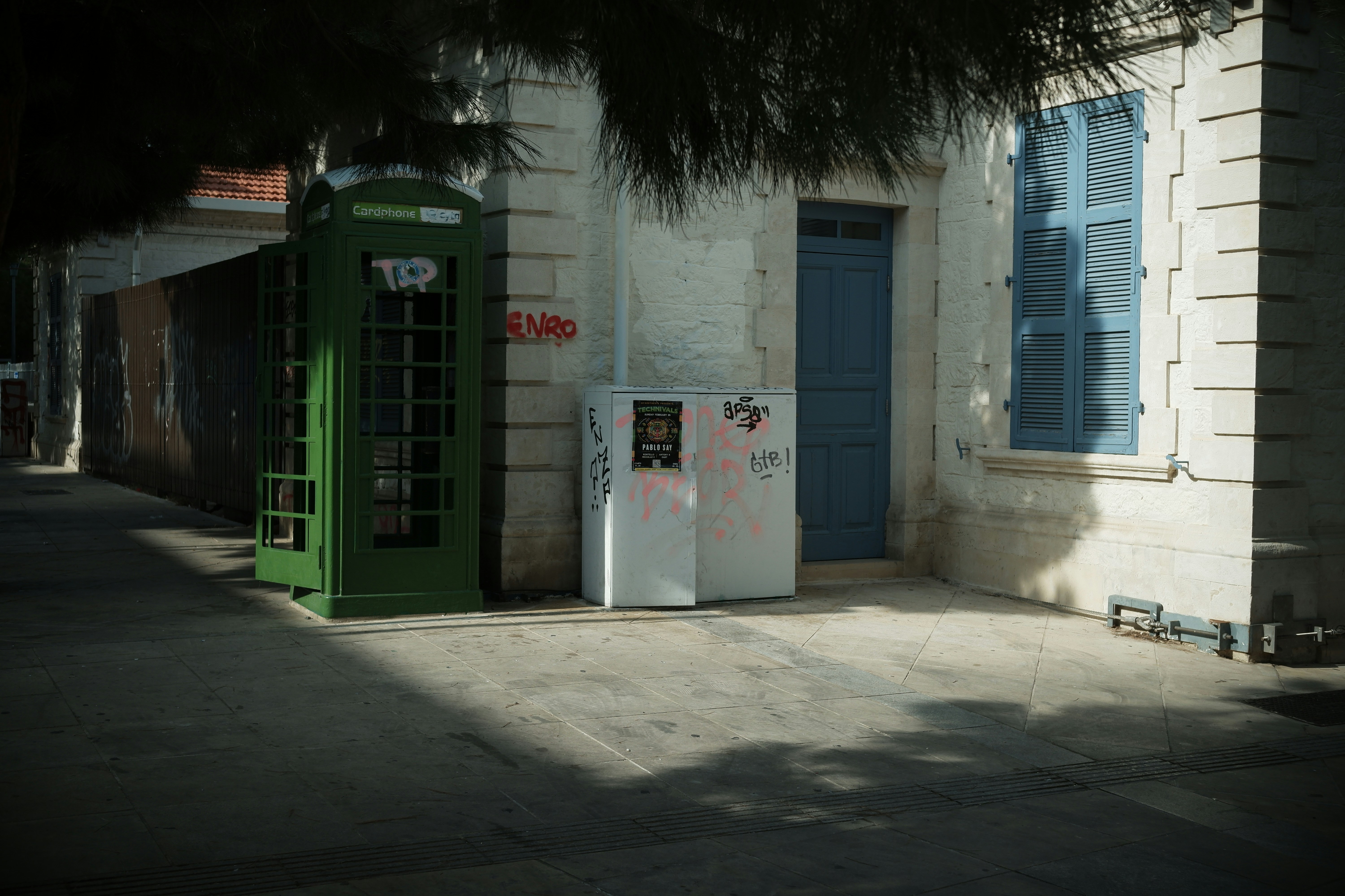 A green phone booth sitting on the side of a building photo – Free ...