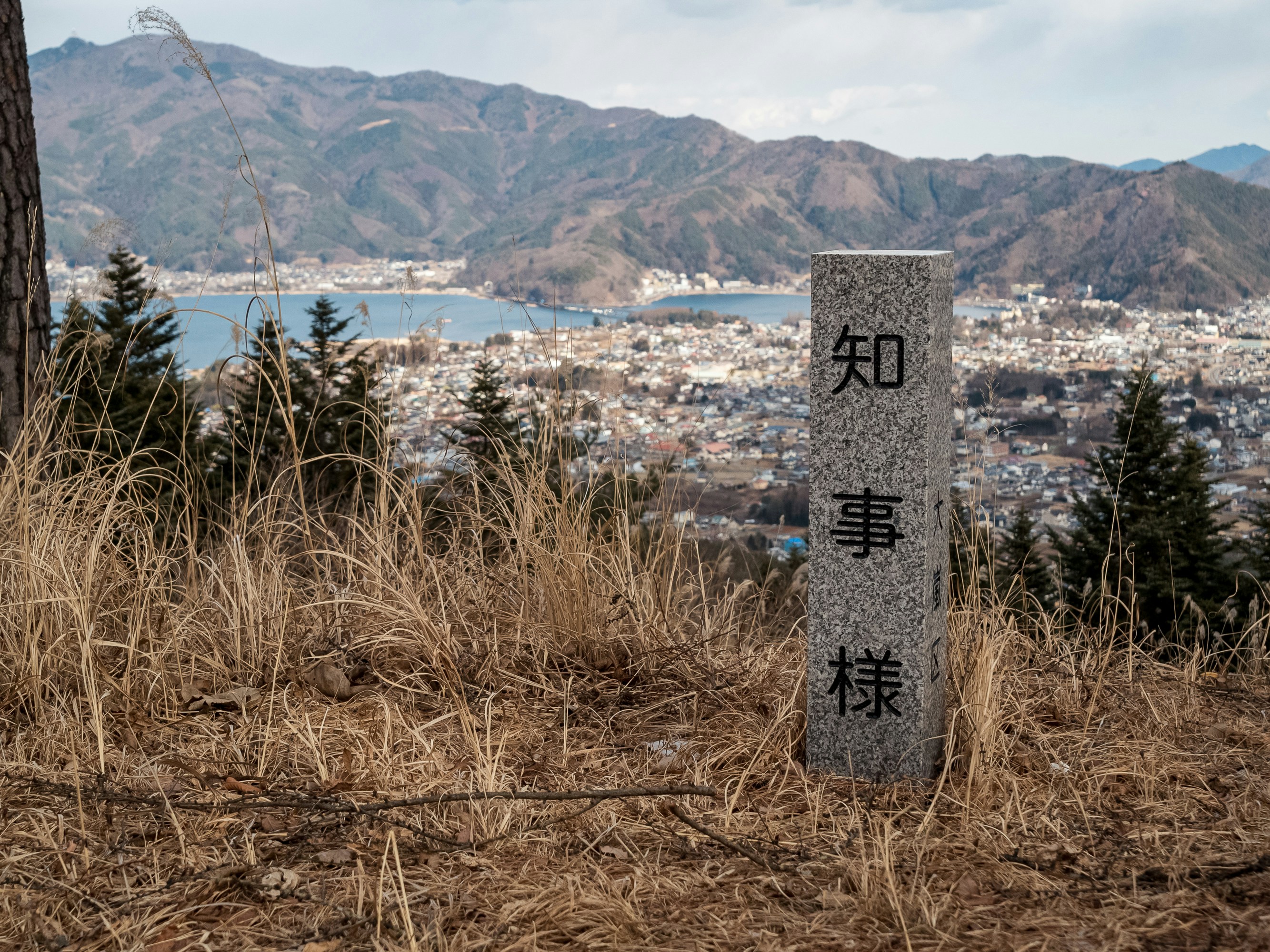 Granite Kanji Marker Framing a Coastal Town from a Windswept Hill