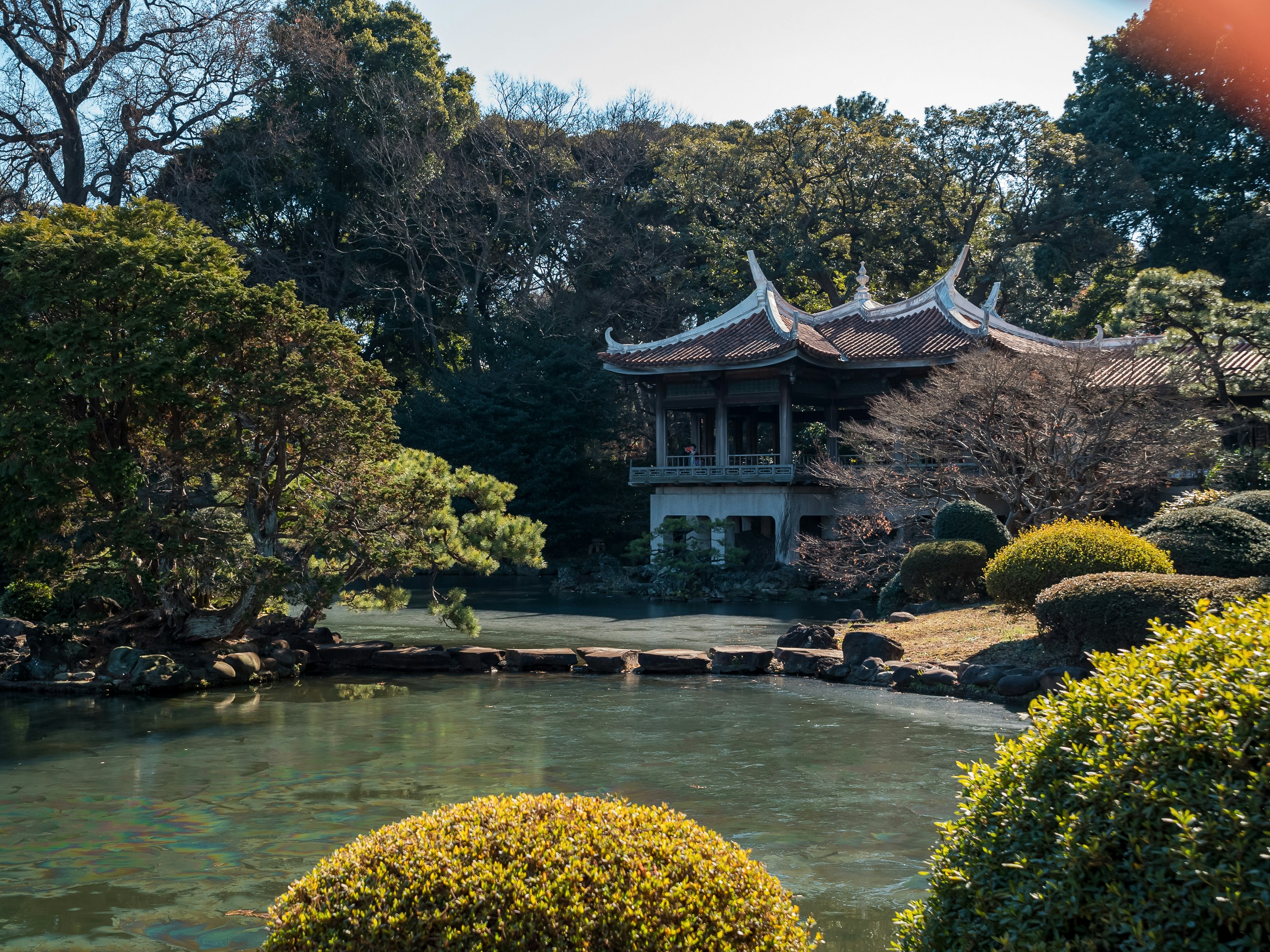 Traditional Japanese architecture nestled among lush greenery and a tranquil pond, reflecting the beauty of nature.