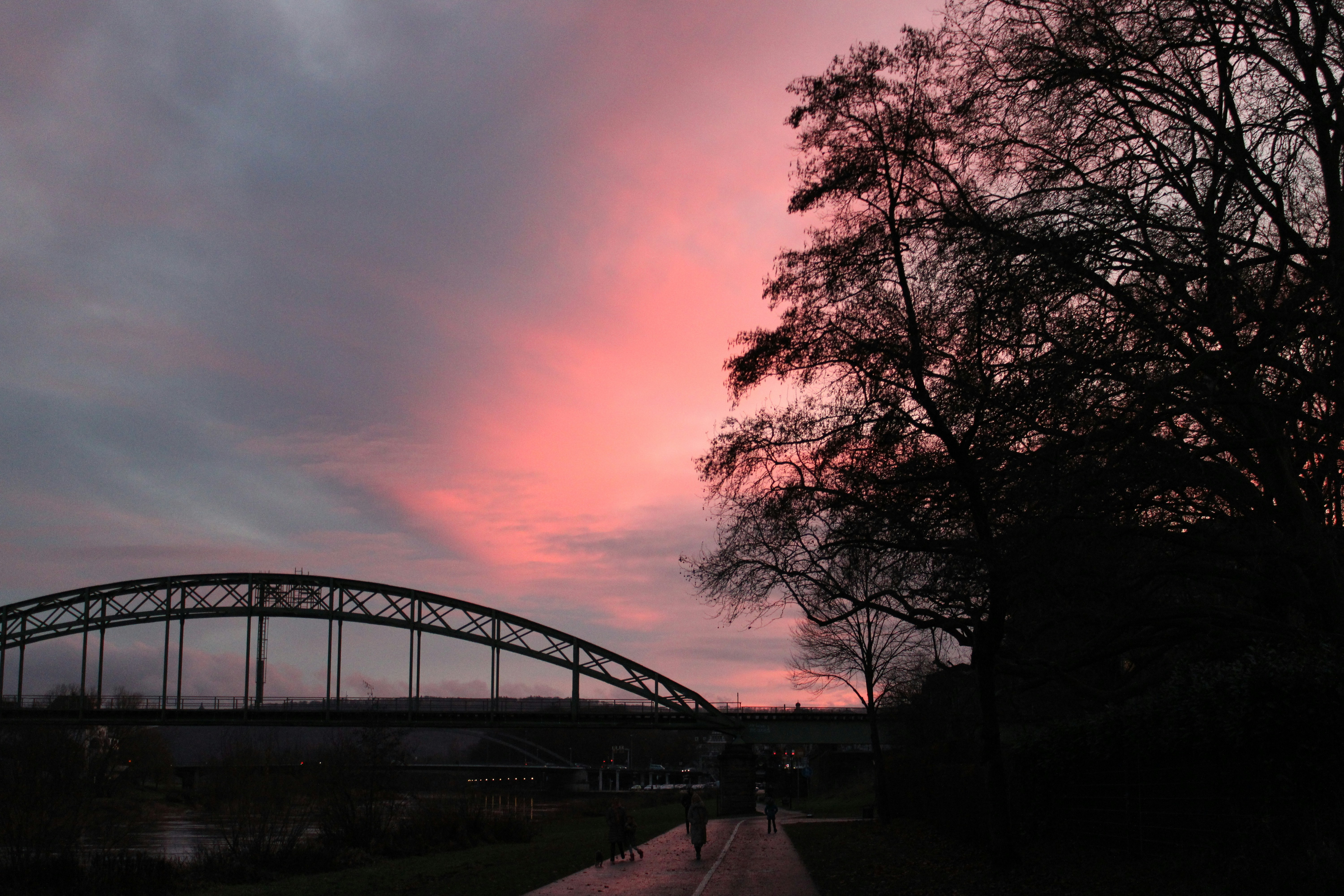 Crimson Skies Over an Arched Bridge: Sunset by the Riverwalk