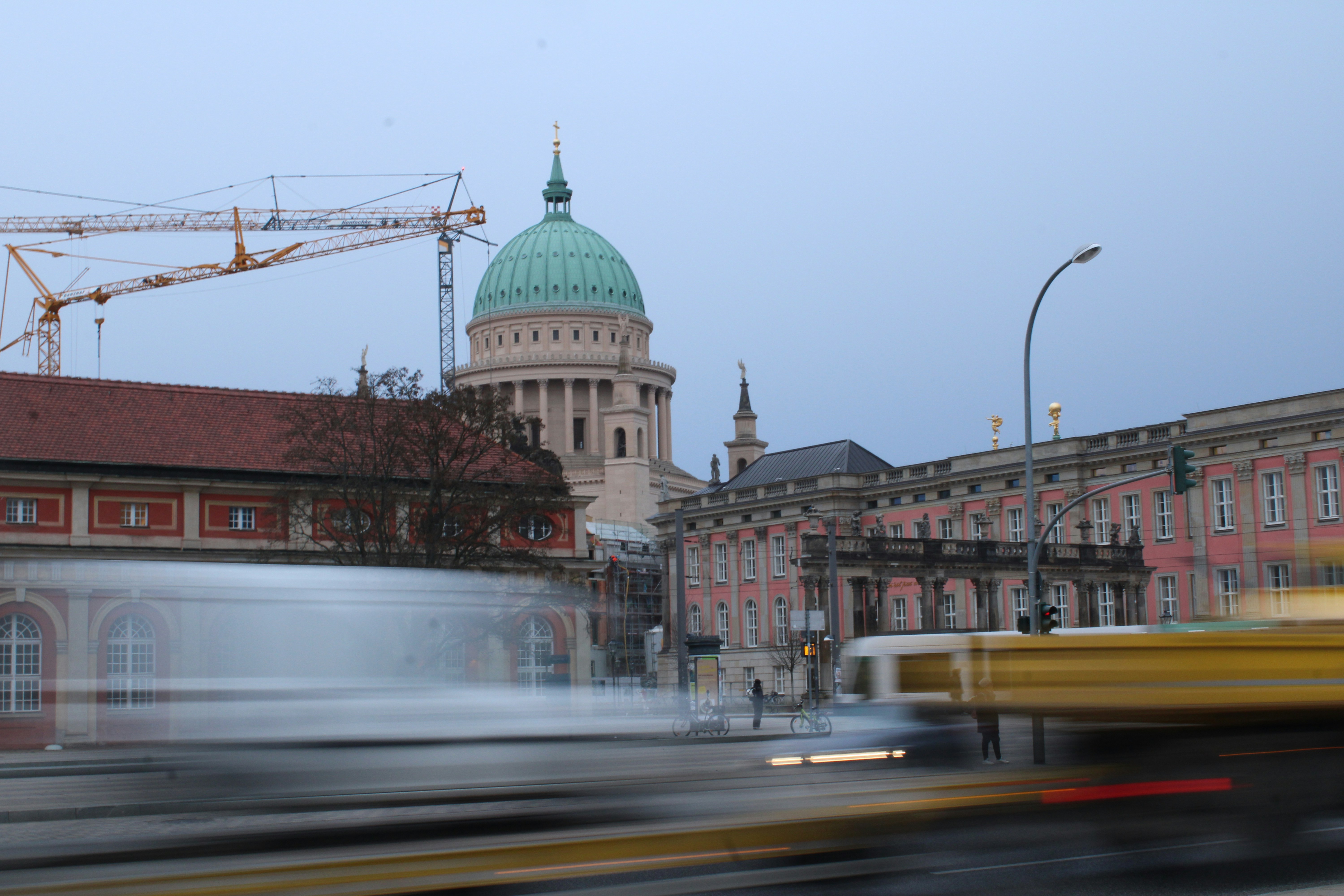 Traffic blurs past historical architecture under a twilight sky.