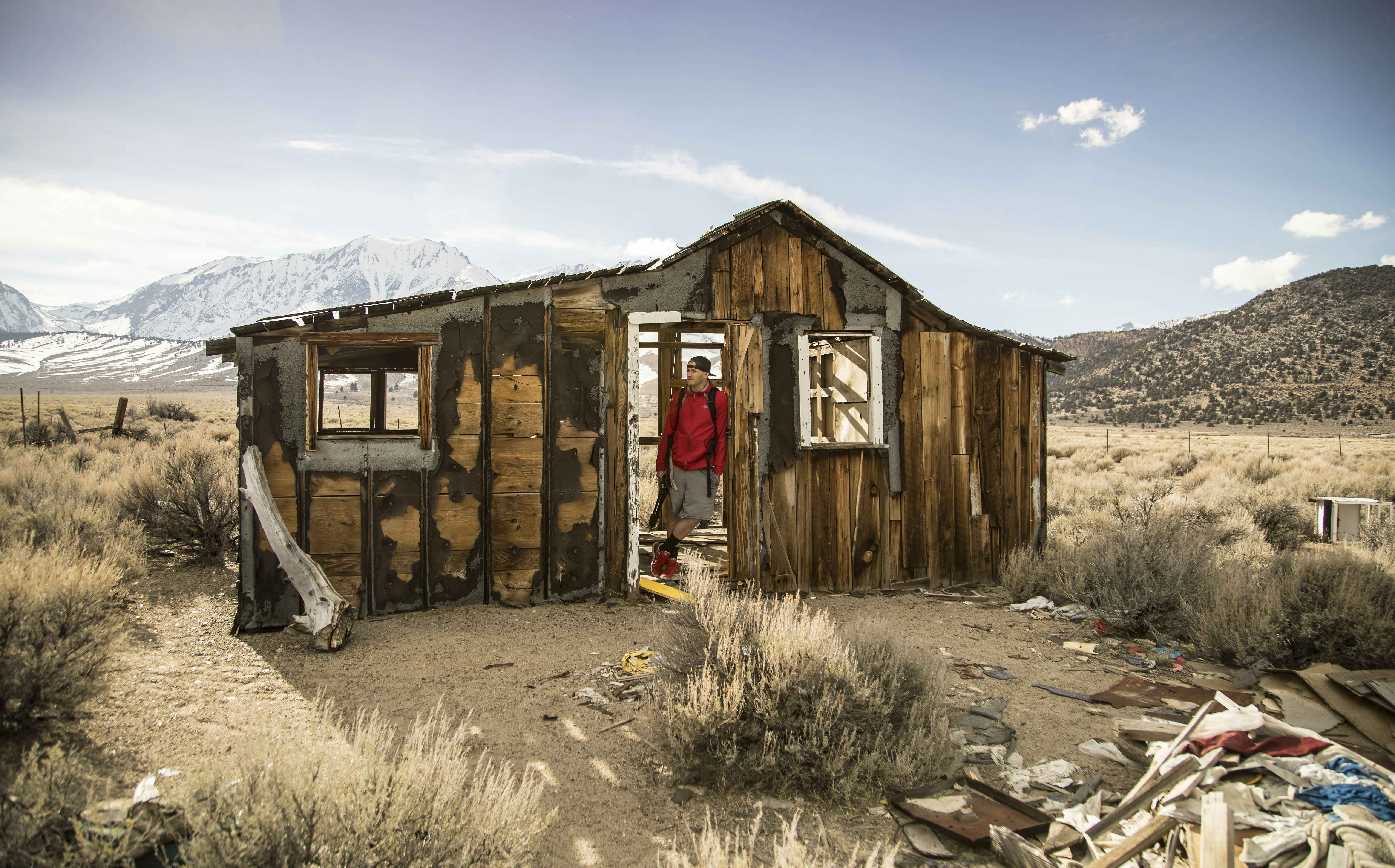 A man standing outside of a shack in the desert photo – Free Shelter ...