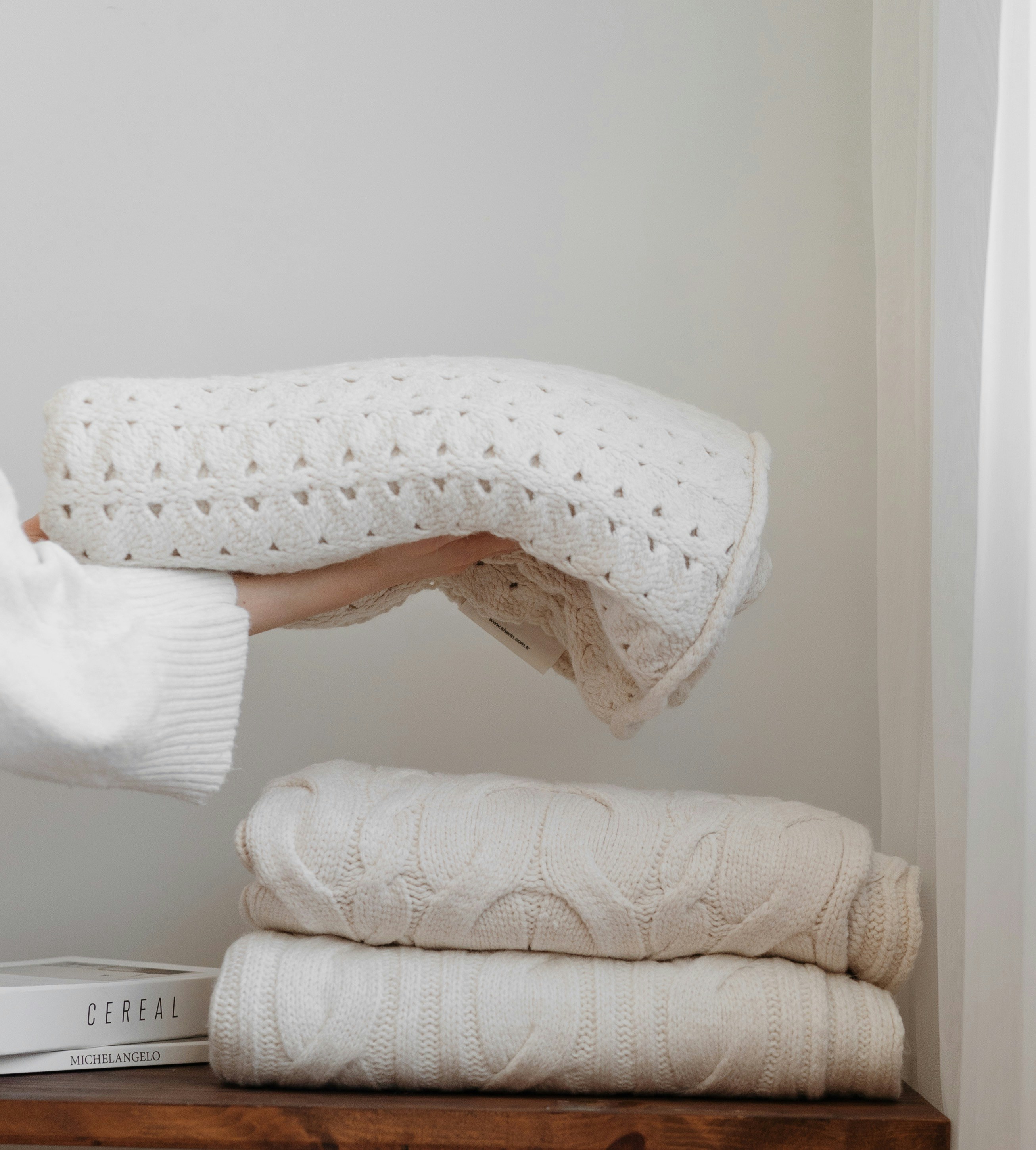 A person holding a blanket over a stack of blankets photo – Free Towel ...