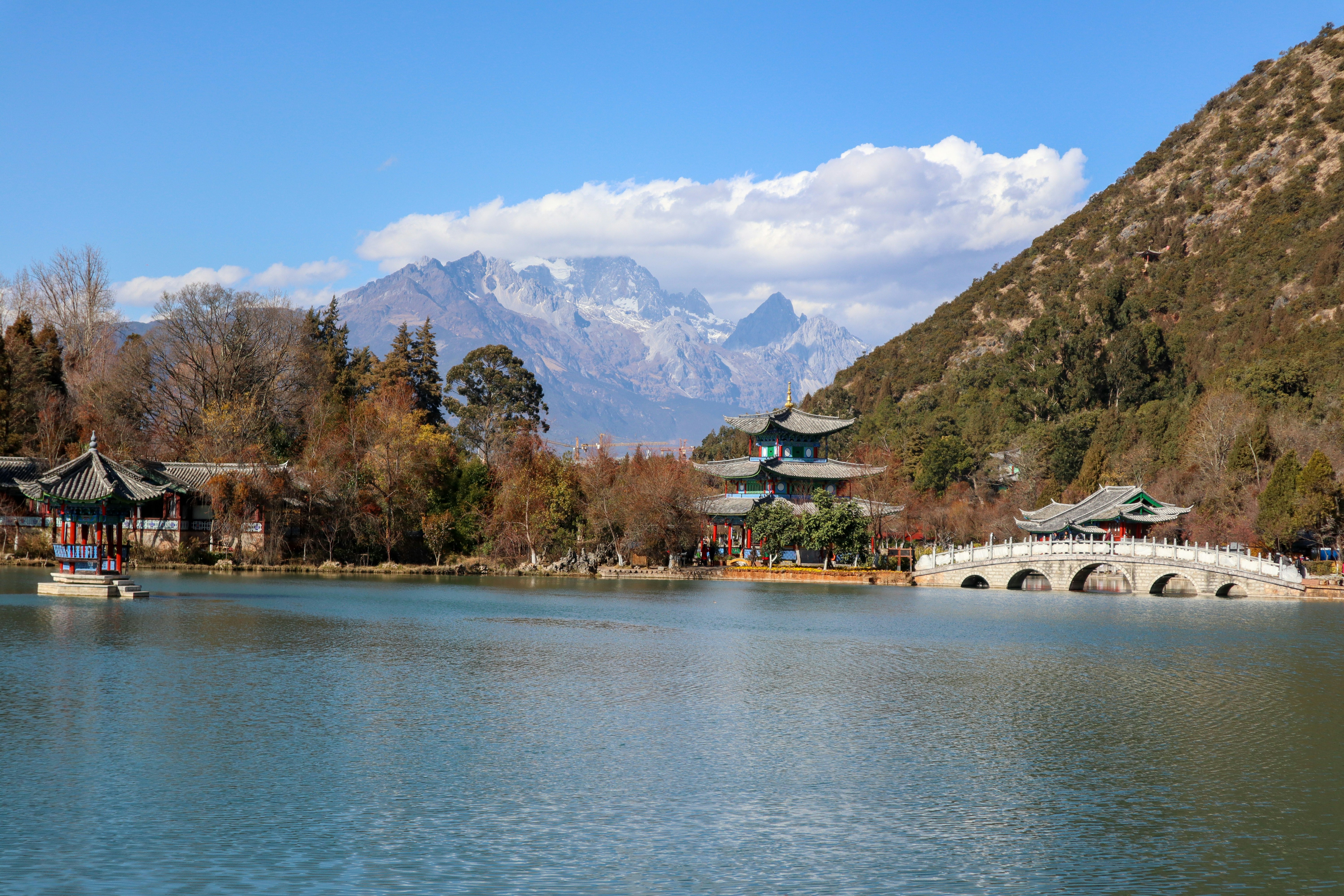 A lake with a bridge and mountains in the background photo – Free ...