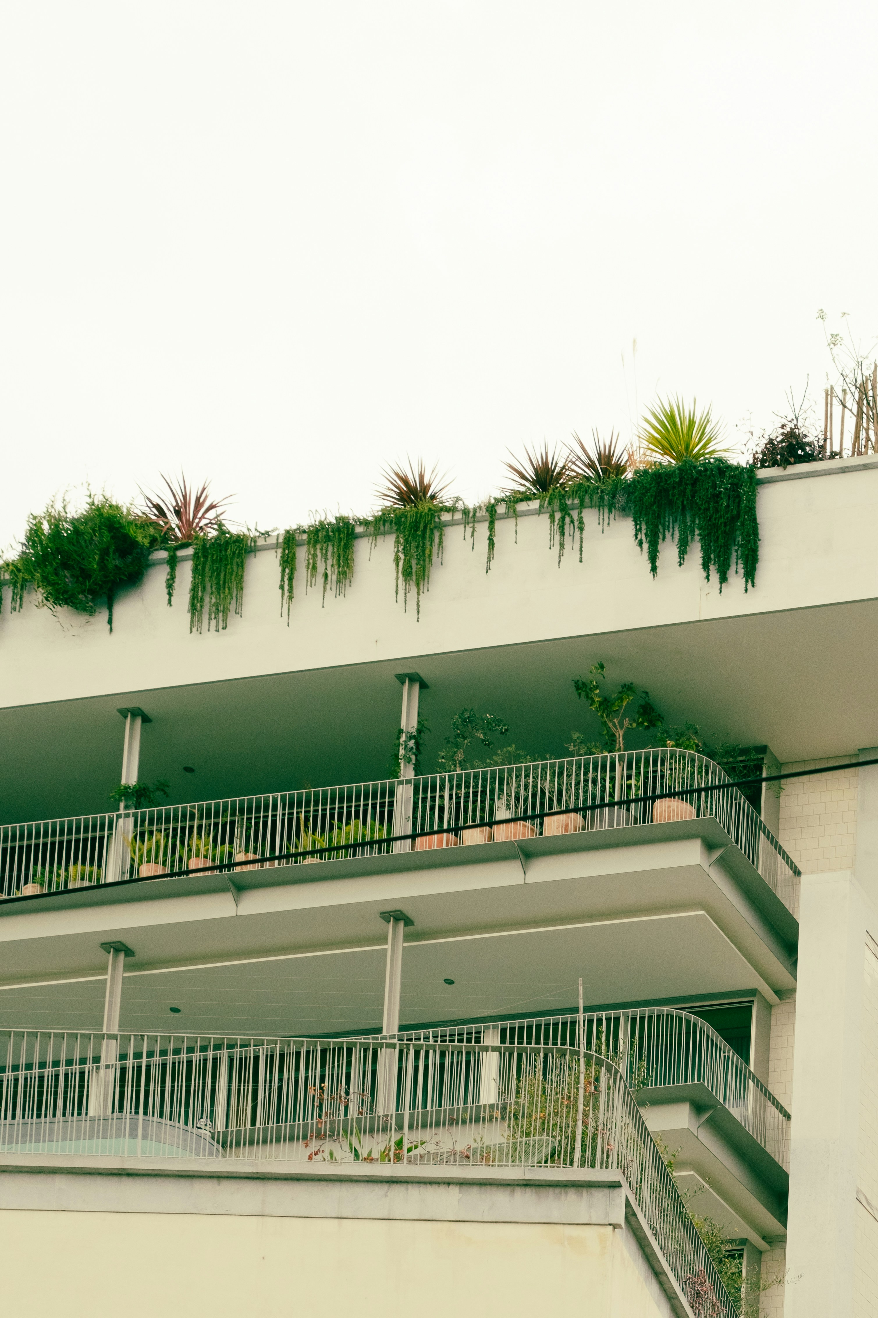 an apartment building with plants growing on the balconies