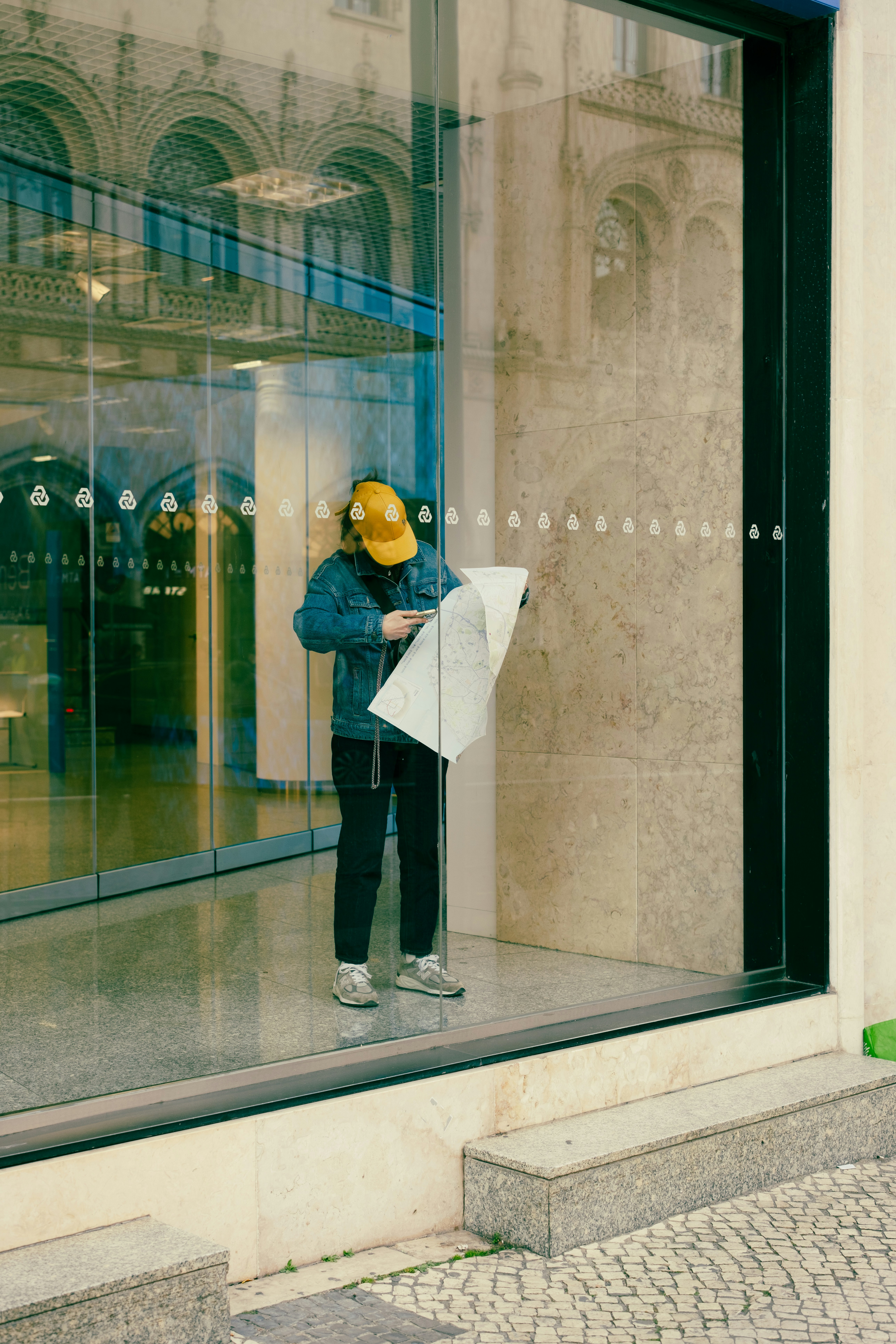 Yellow-Hatted Navigator Studying a City Map Through a Glass Facade