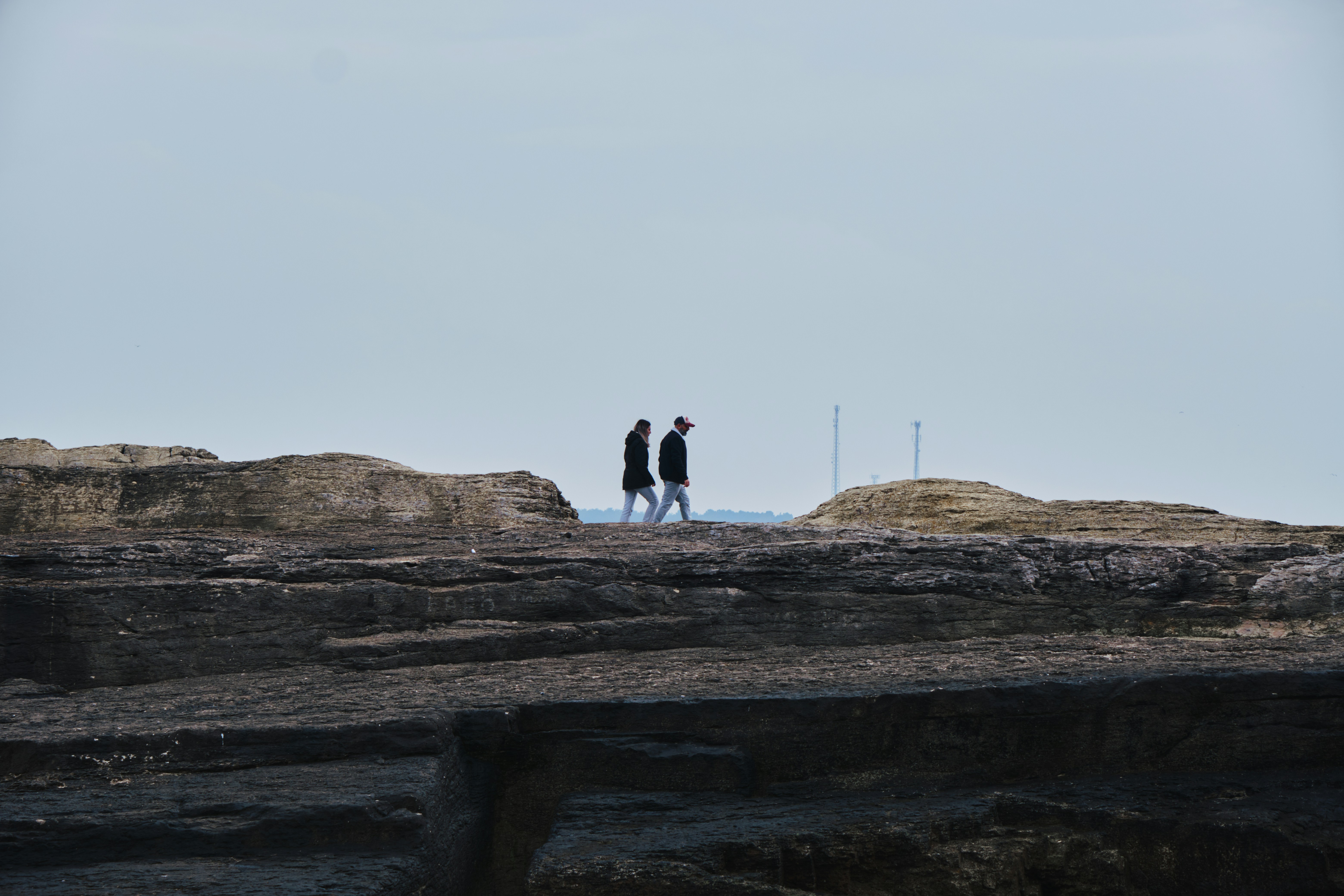 Coastal Promenade: Two Figures Traversing a Weathered Rim