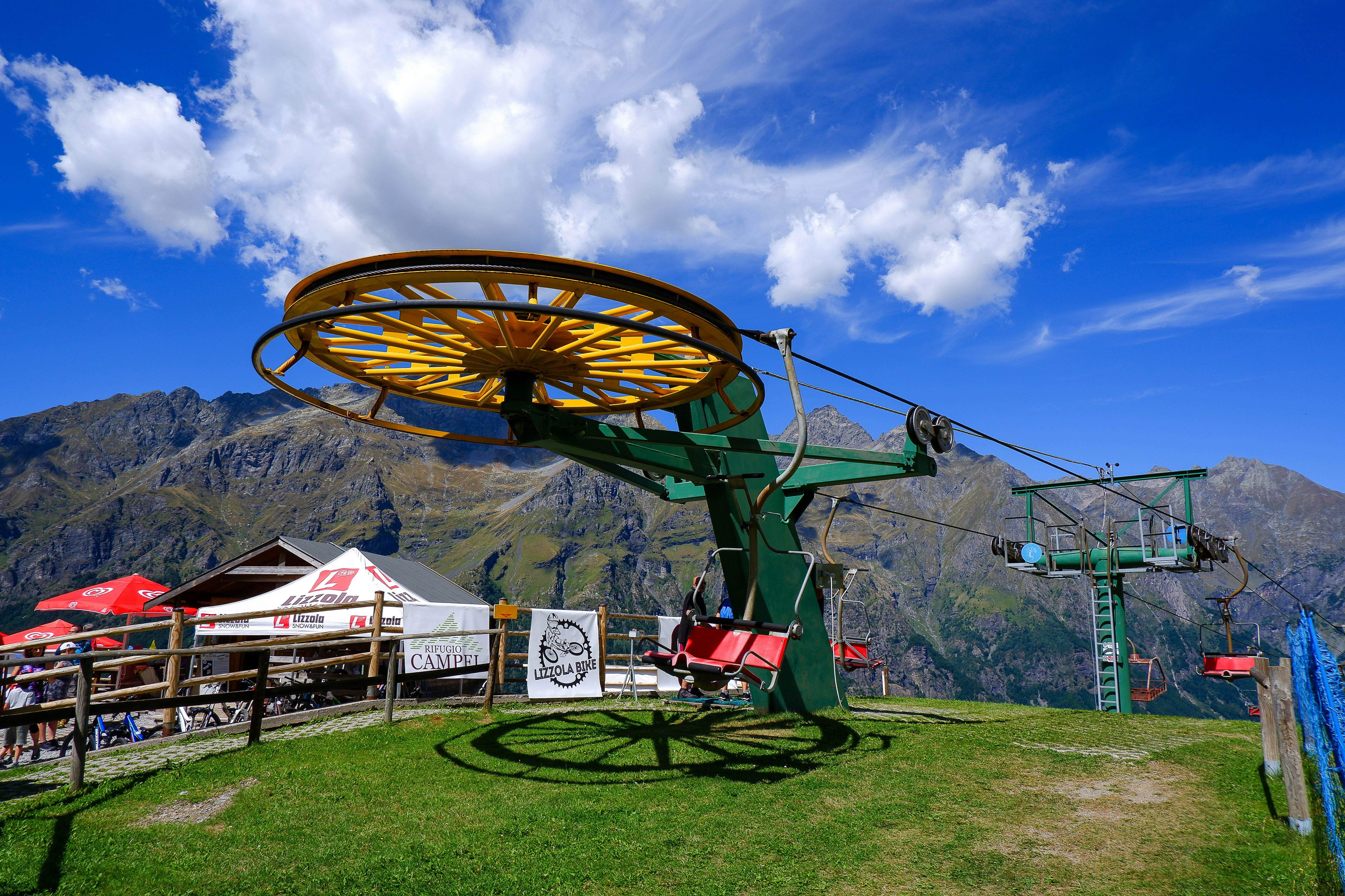 Alpine Circle: The Giant Chairlift Wheel Against Sky and Peaks