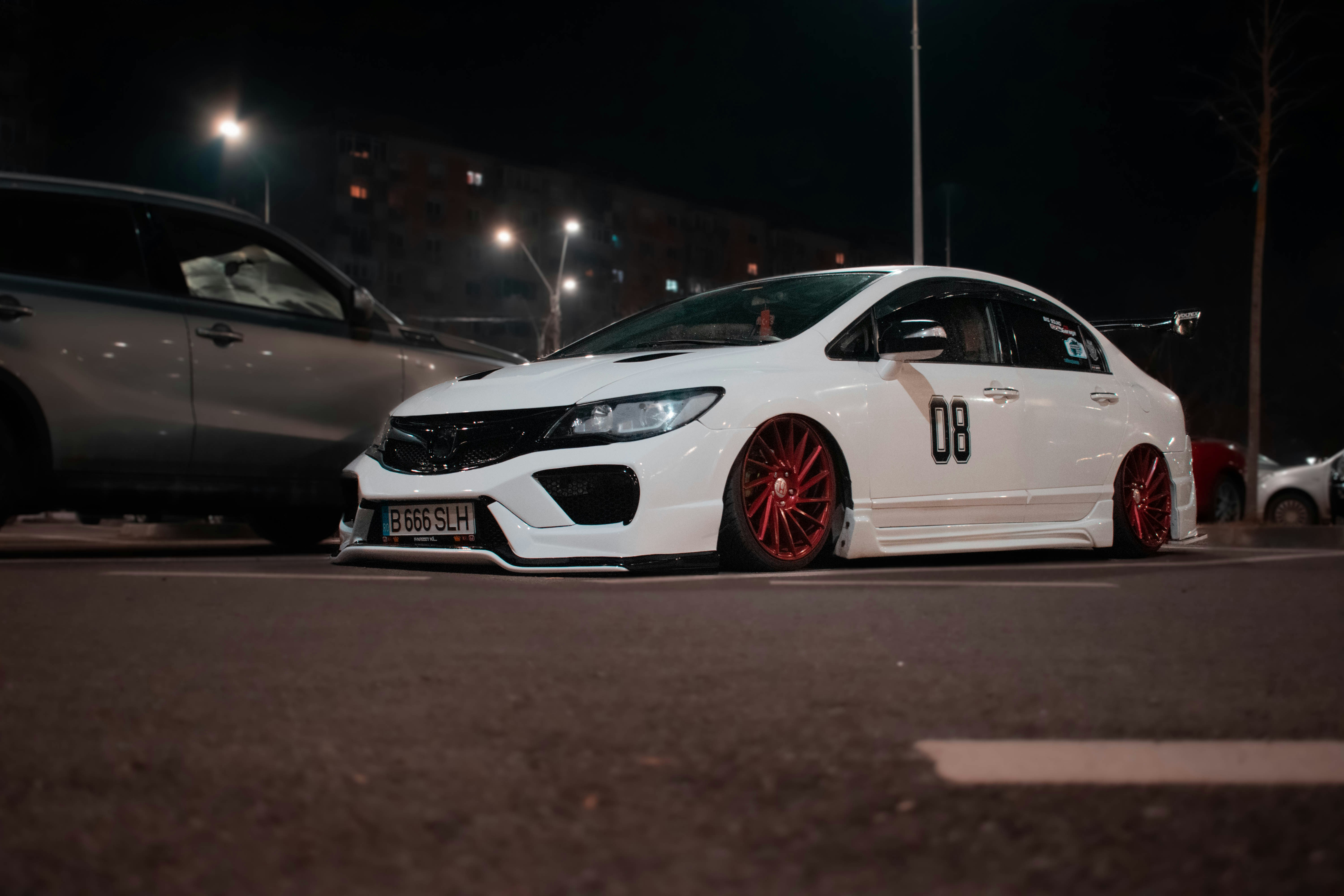 Night Rally: White hatchback with ruby wheels under streetlight glow
