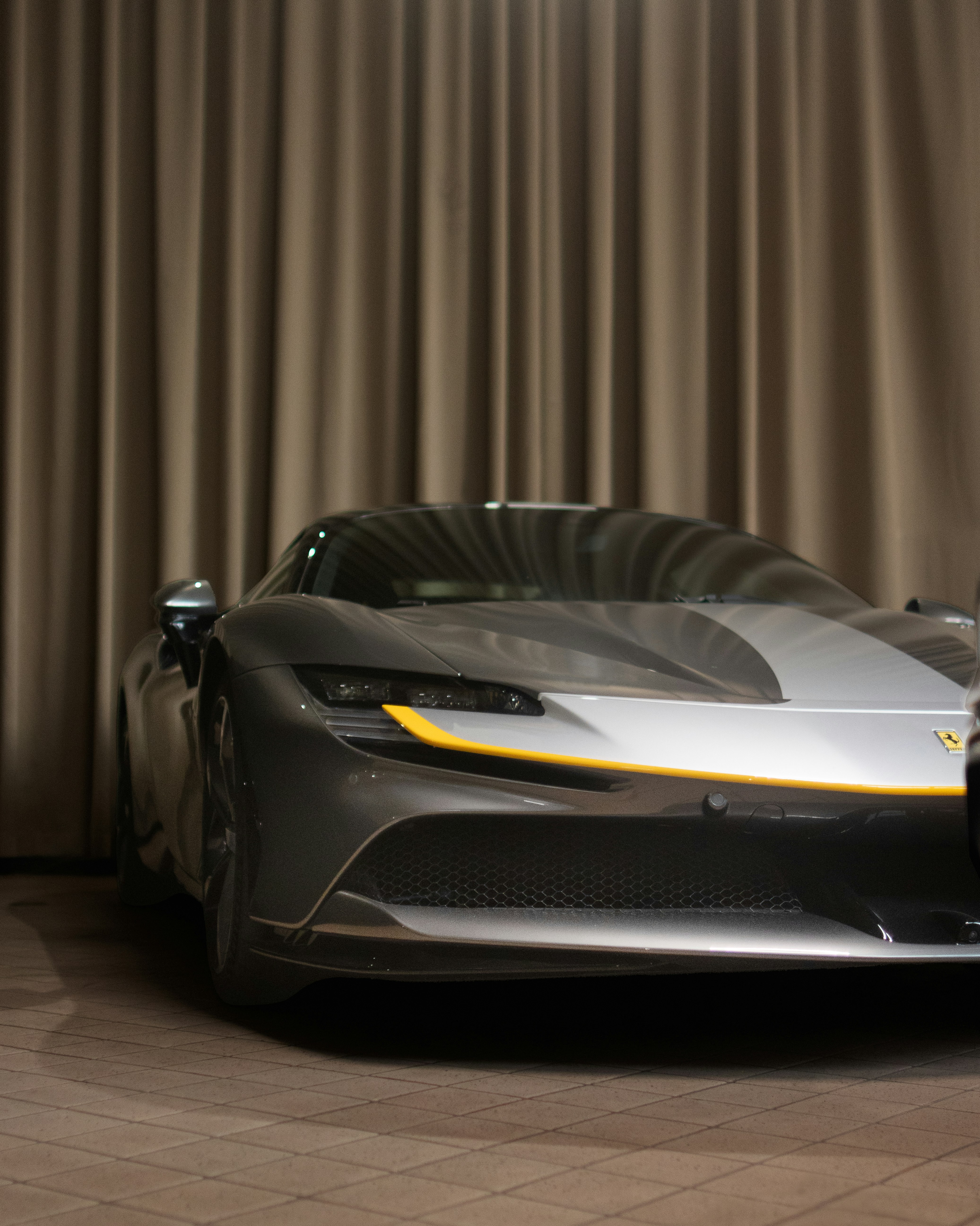 A silver and yellow sports car sitting in front of a curtain photo ...