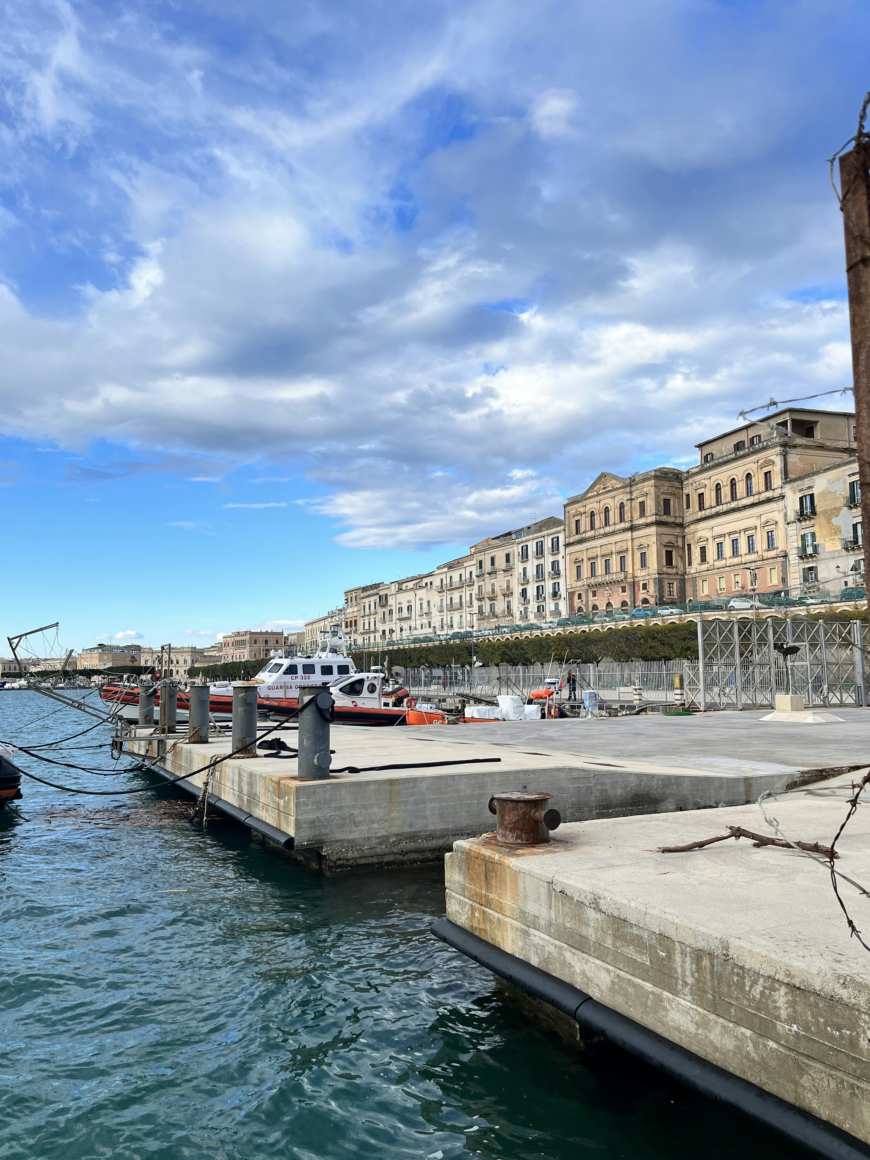 Harbor Terrace: Sunlit brick facades and sailing boats along a Mediterranean quay