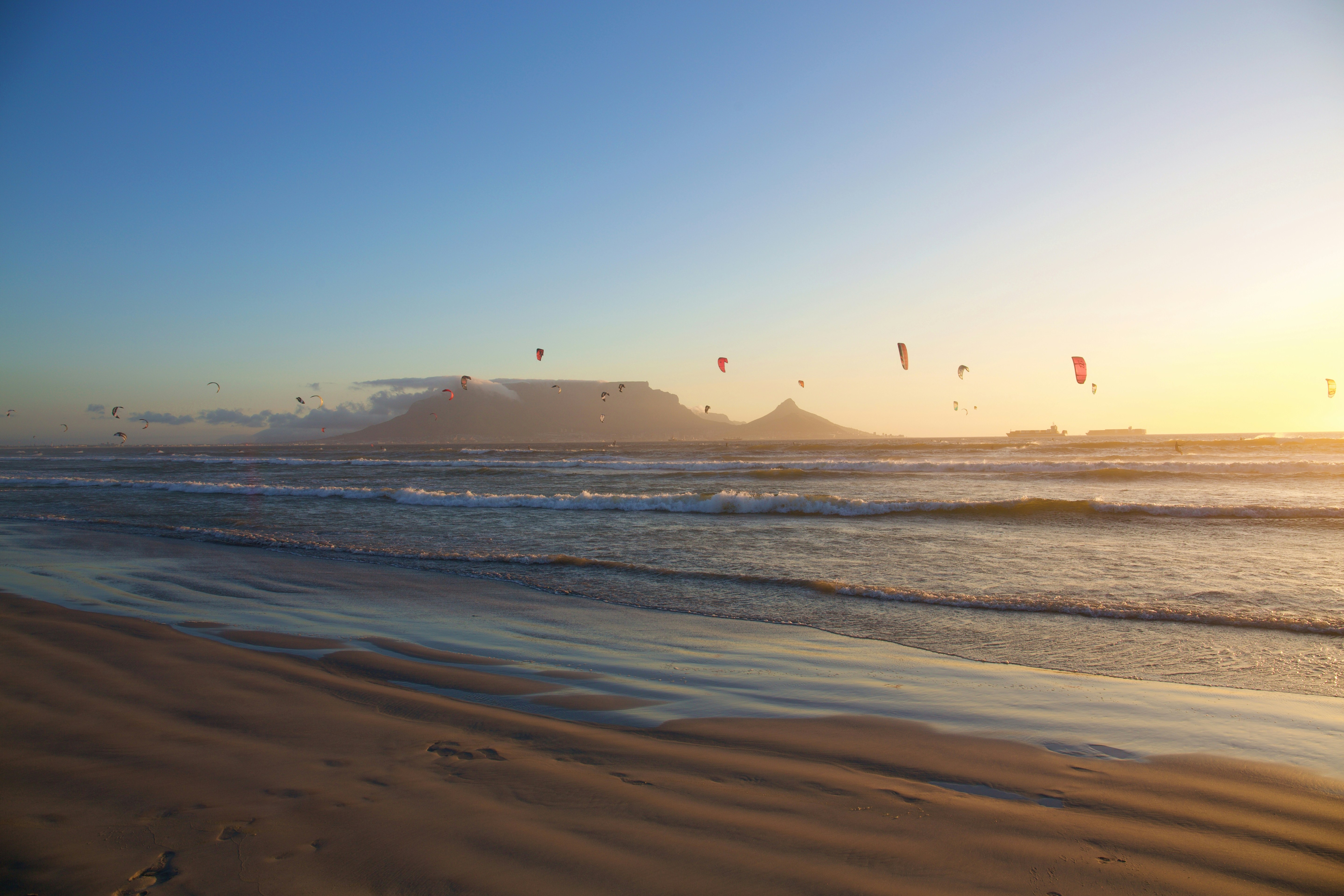 A group of kites flying over the ocean at sunset photo – Free Table ...
