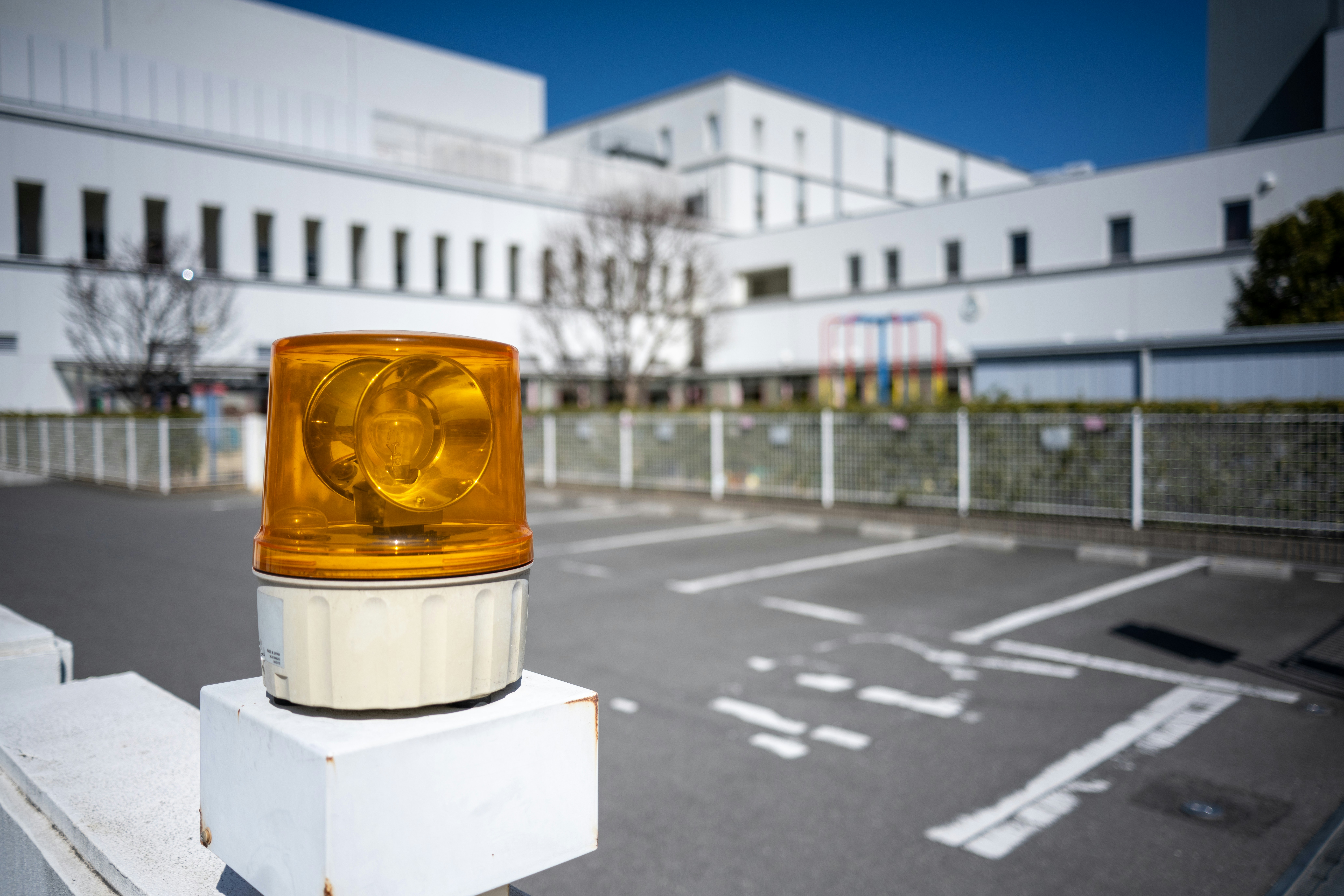 Amber Beacon at the Edge of a Quiet Campus Parking Lot