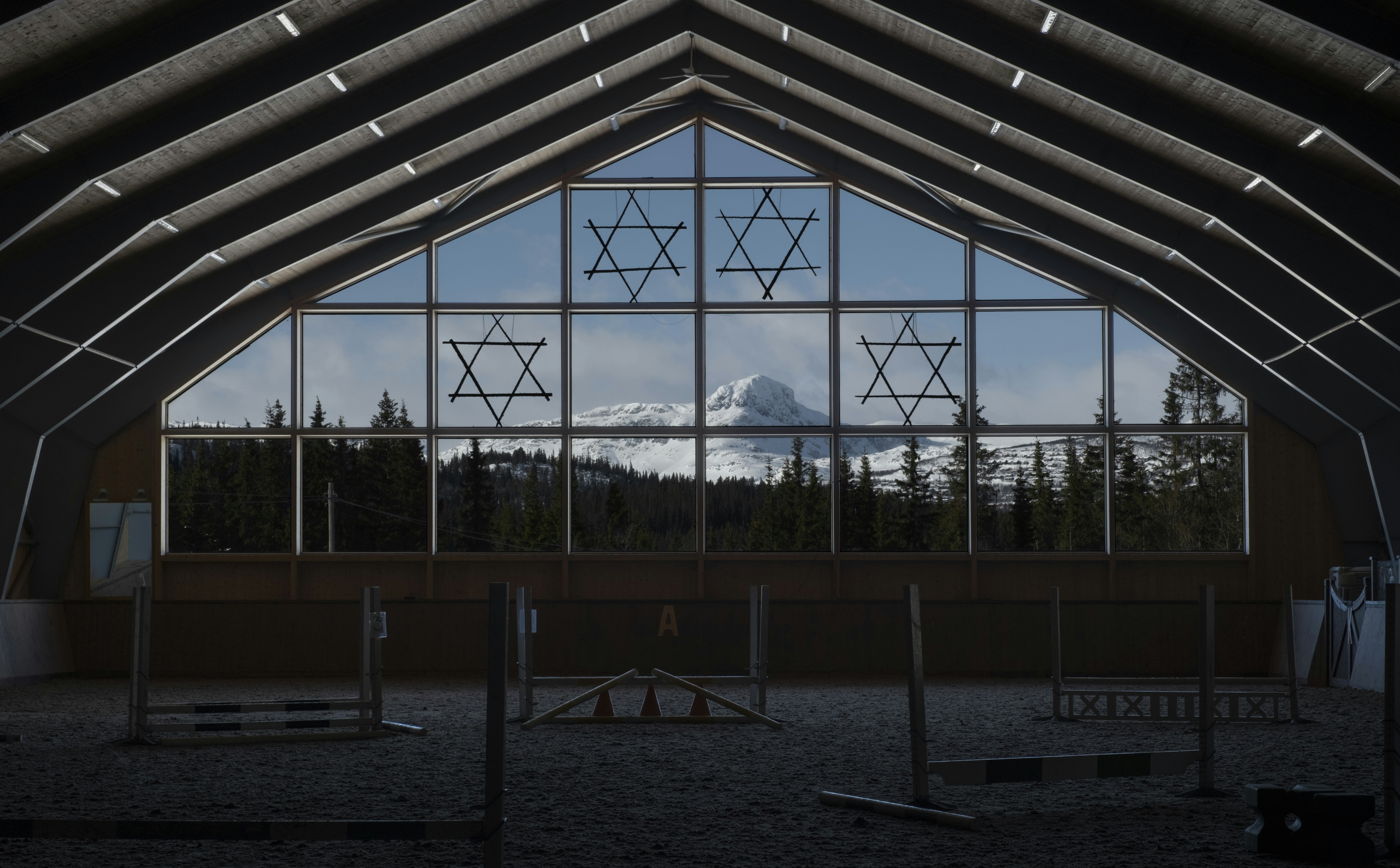 Snow-Kissed Peaks Framed by Star Panes in an Empty Indoor Arena
