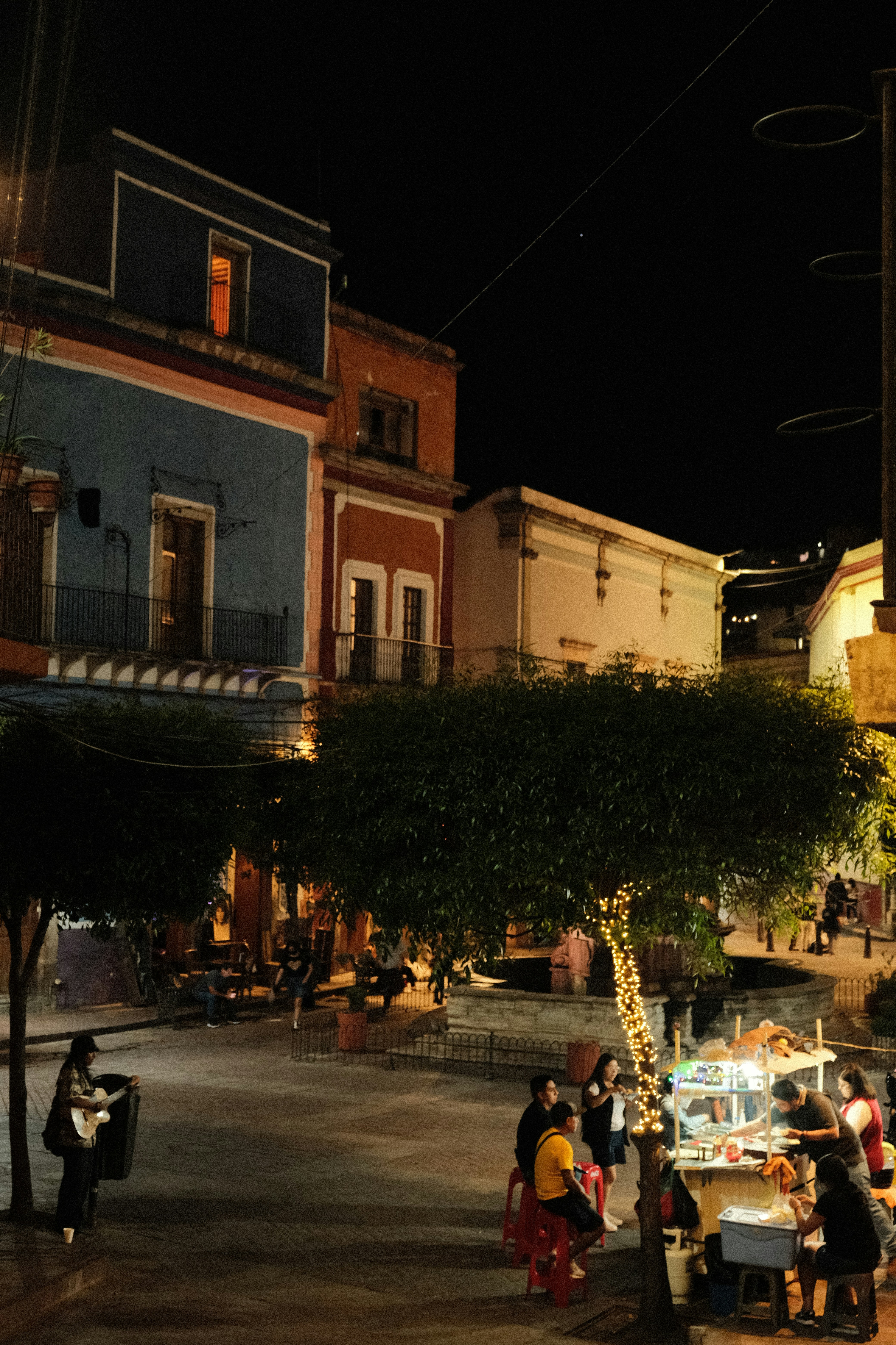 Night Market under Luminous Trees on a Colorful Mediterranean Street