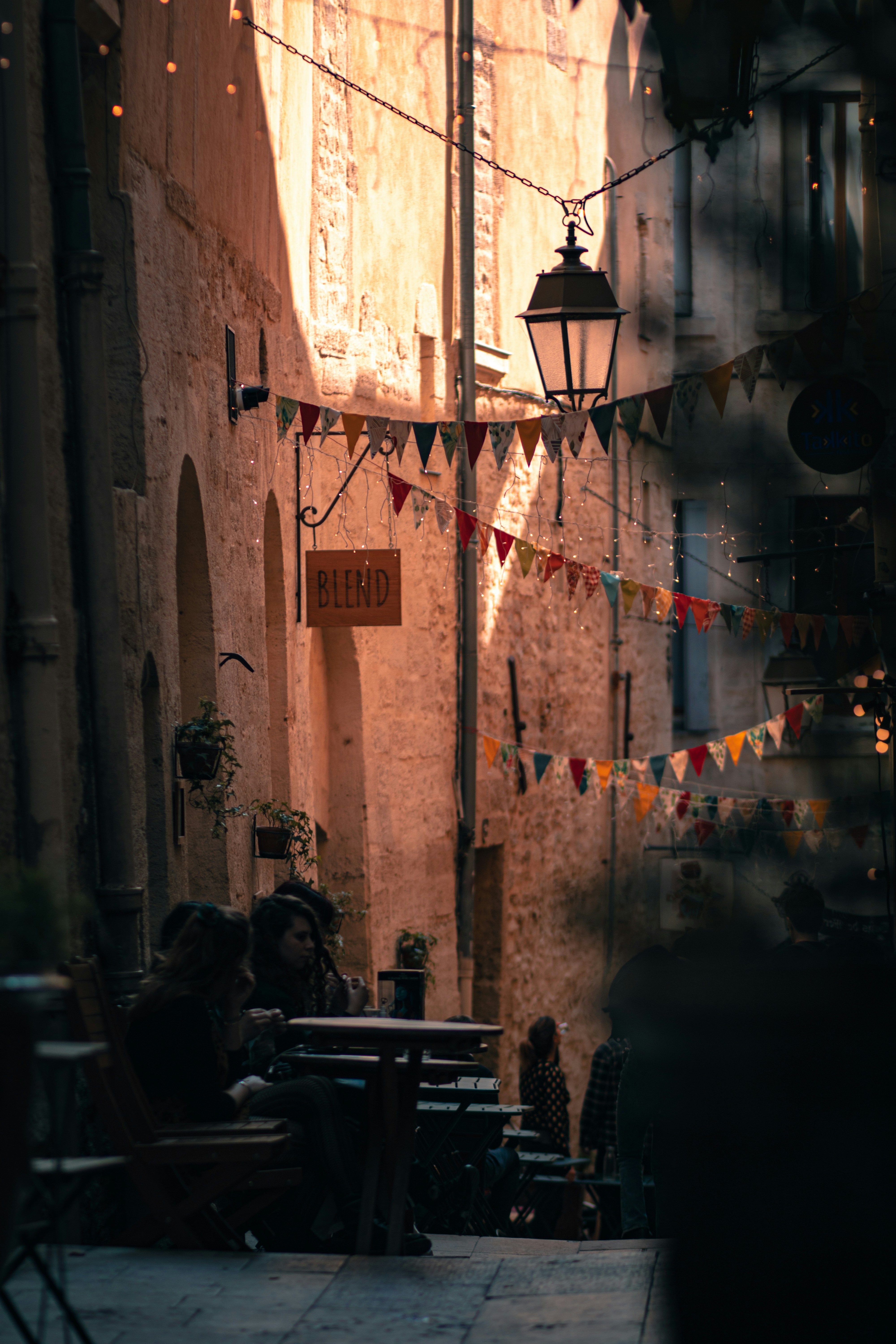Lantern-lit alleyway with festive bunting and shadowed diners