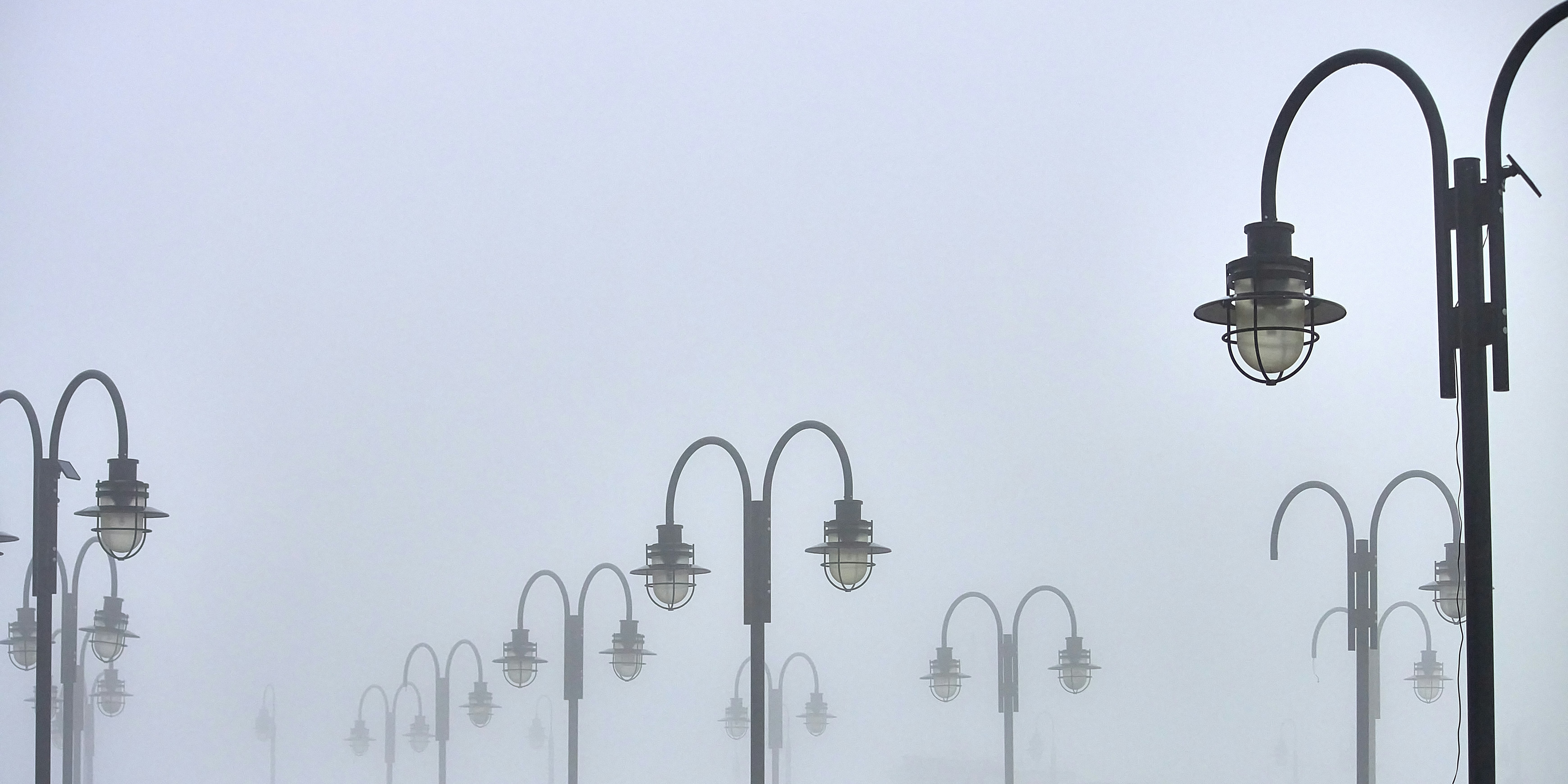 Quiet Row of Arching Lamps on a Misty Pier