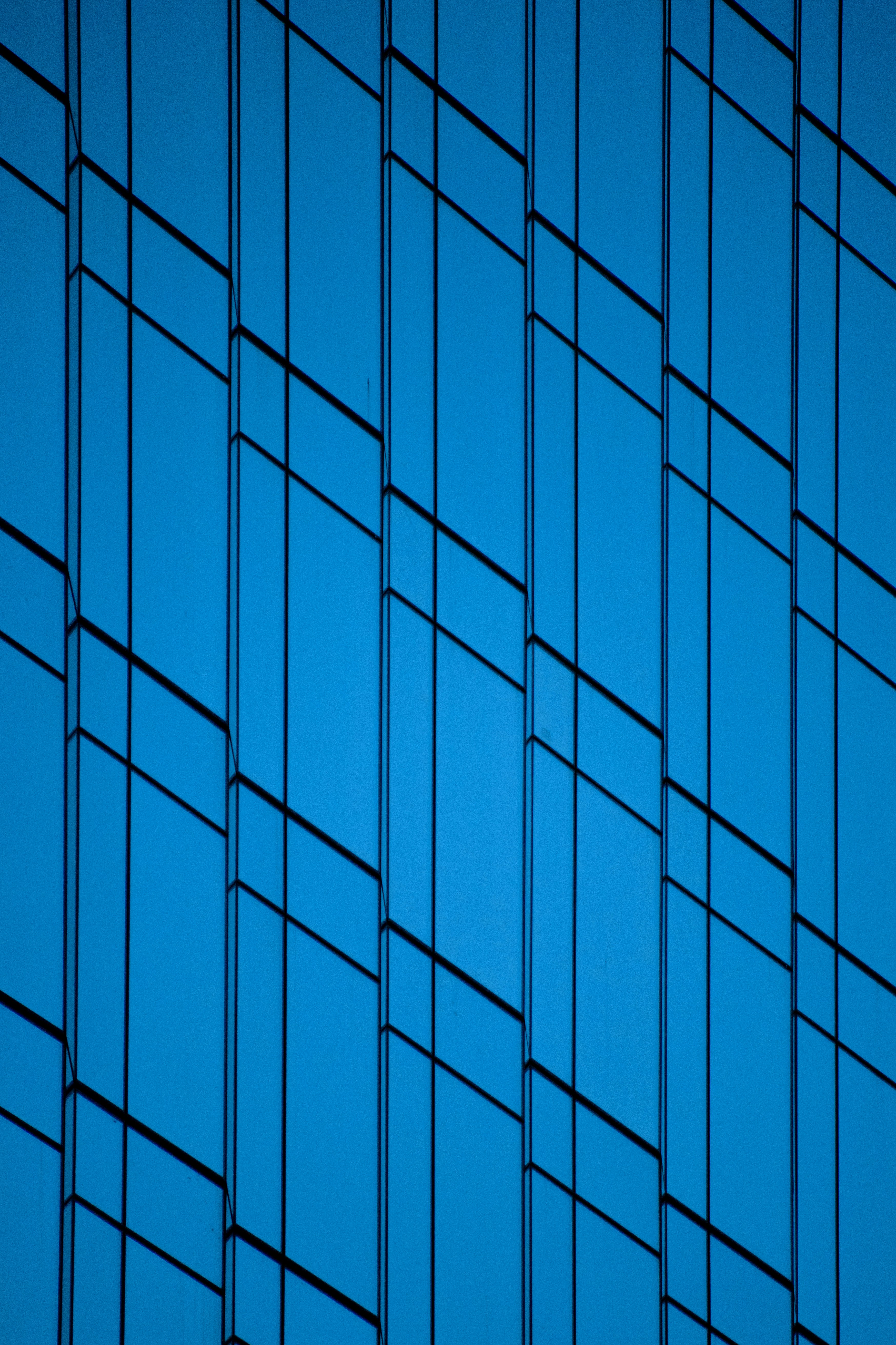 Abstract depiction of a modern building's glass facade with intricate geometric patterns in shades of blue.