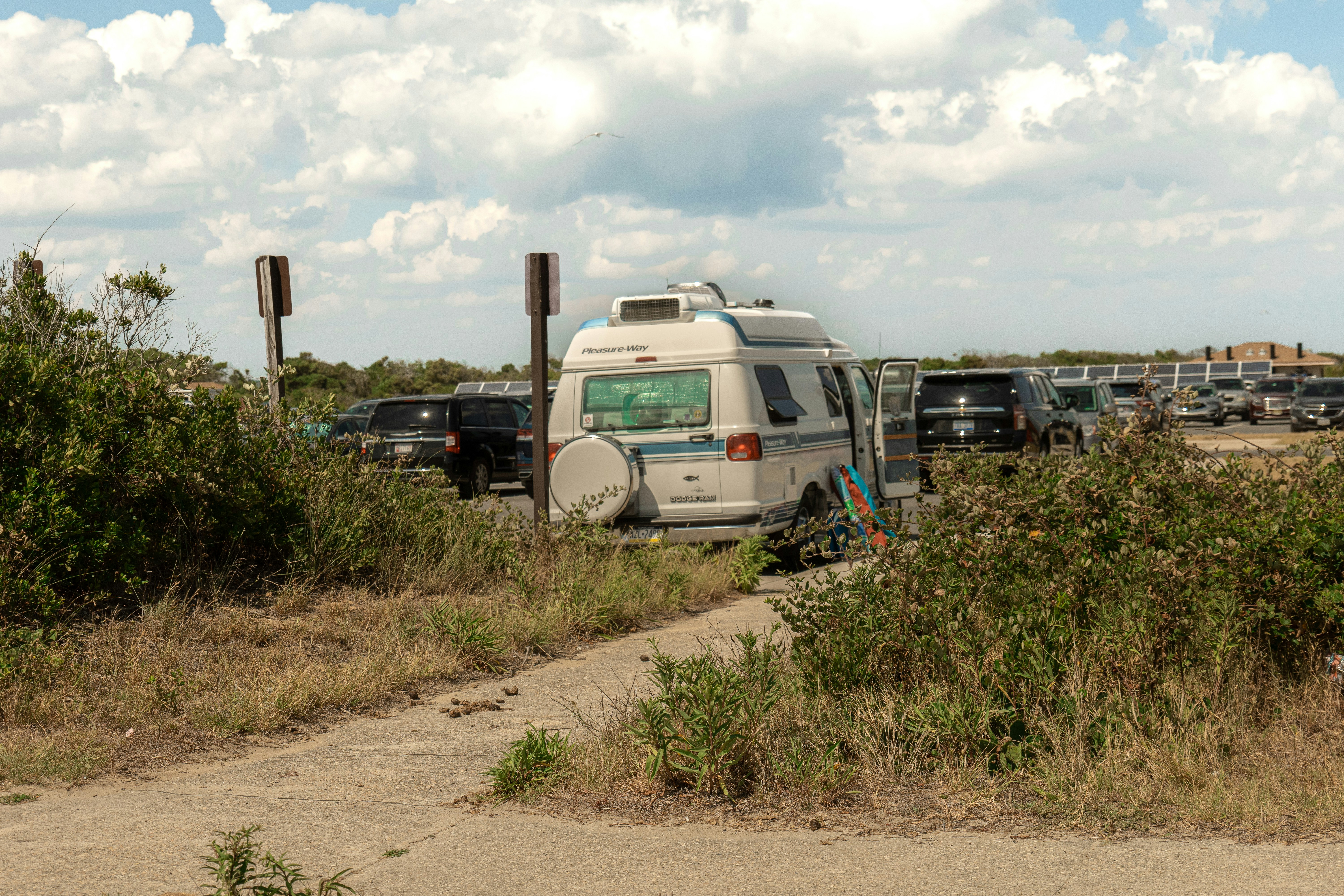 Desert-Edge Stopover: A Weathered Camper Amid a Line of Cars