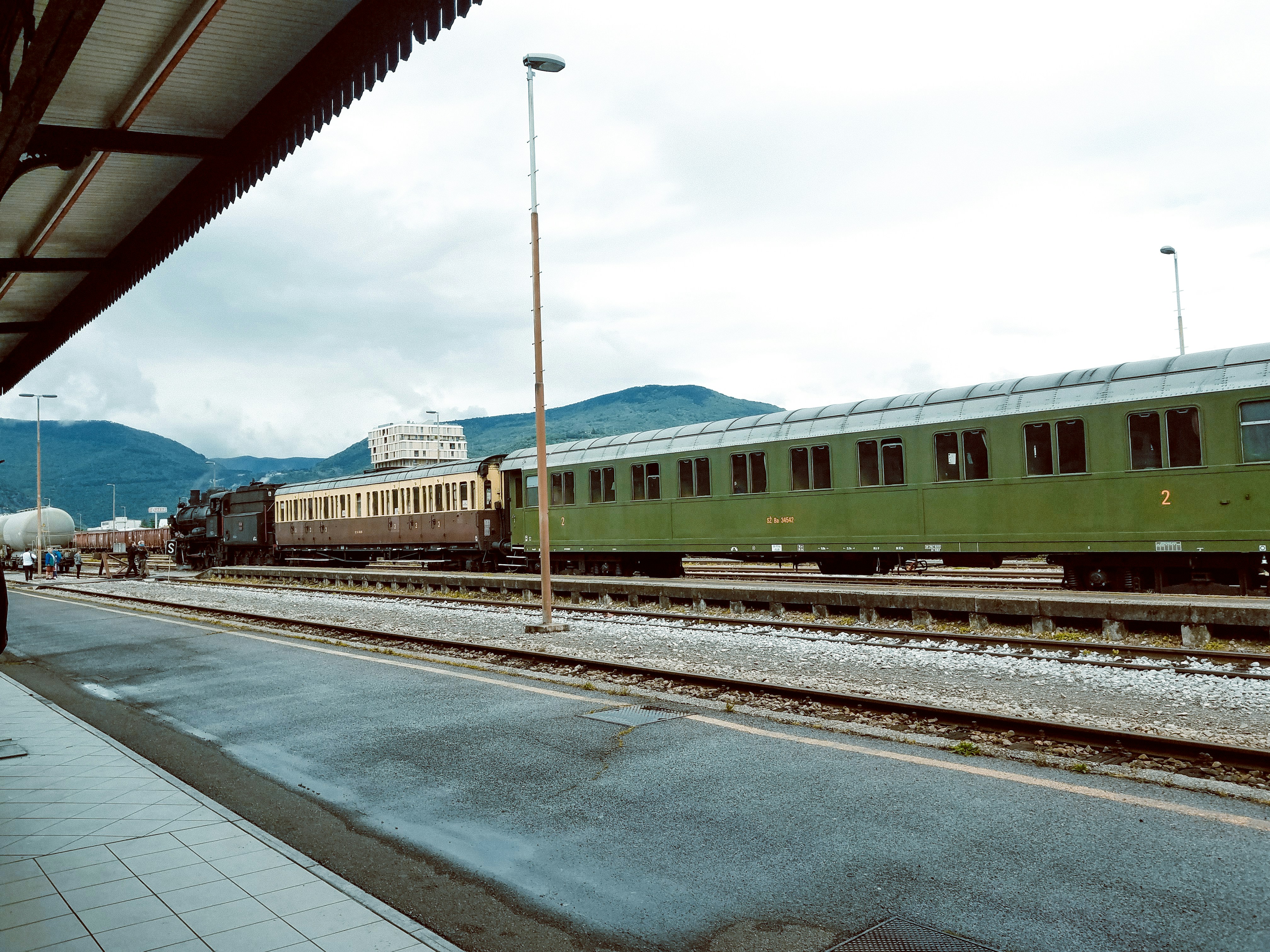A green train traveling down train tracks next to a train station photo ...